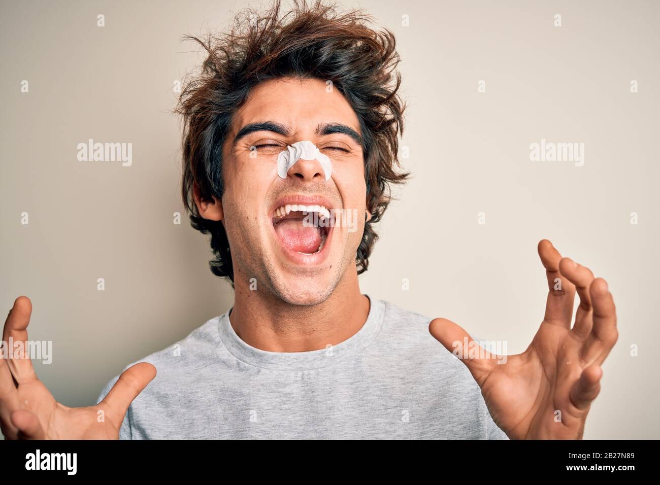 Young handsome man using nose strip standing over isolated white ...