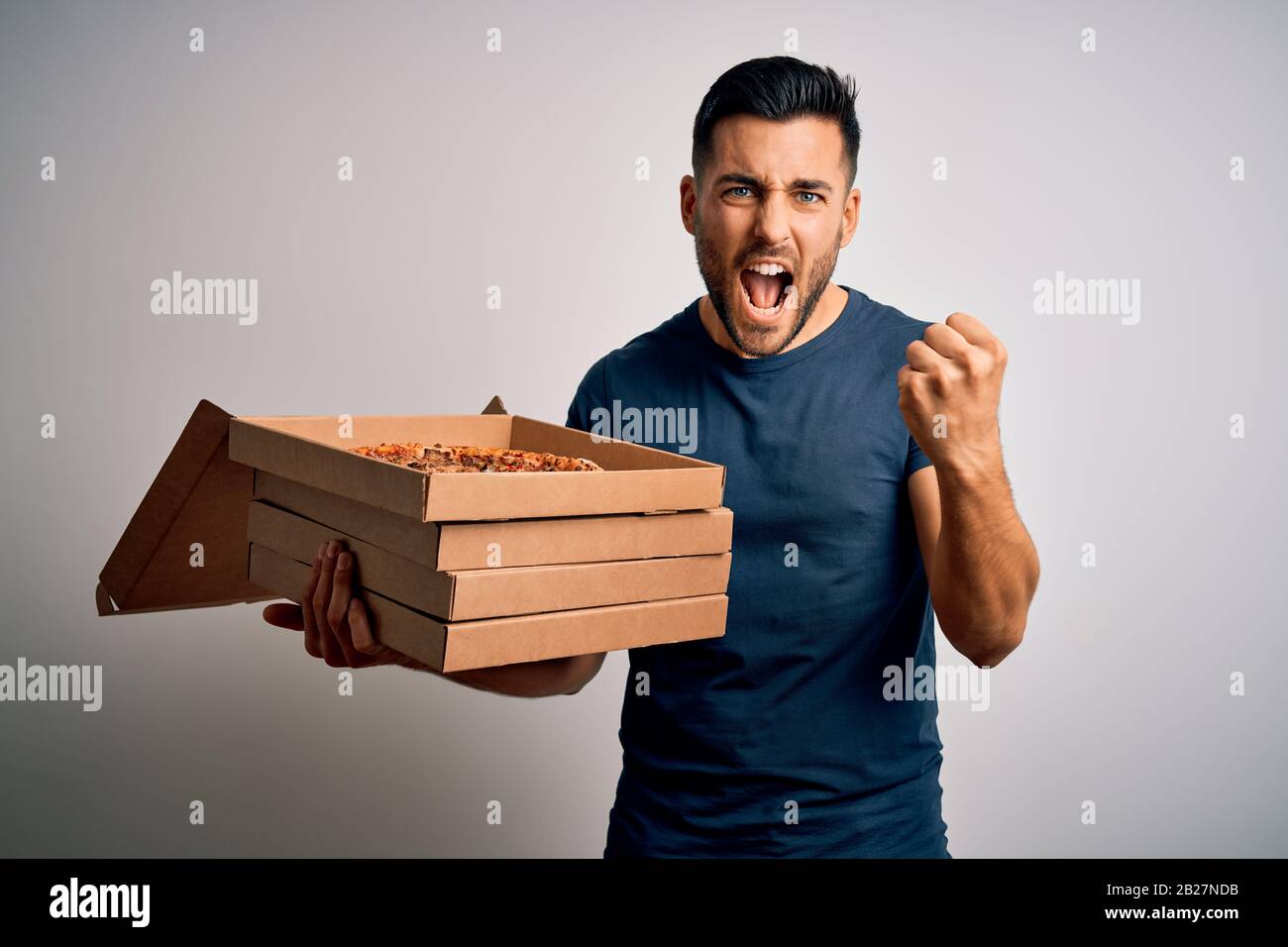 Young handsome man holding delivery boxes with Italian pizza over white ...