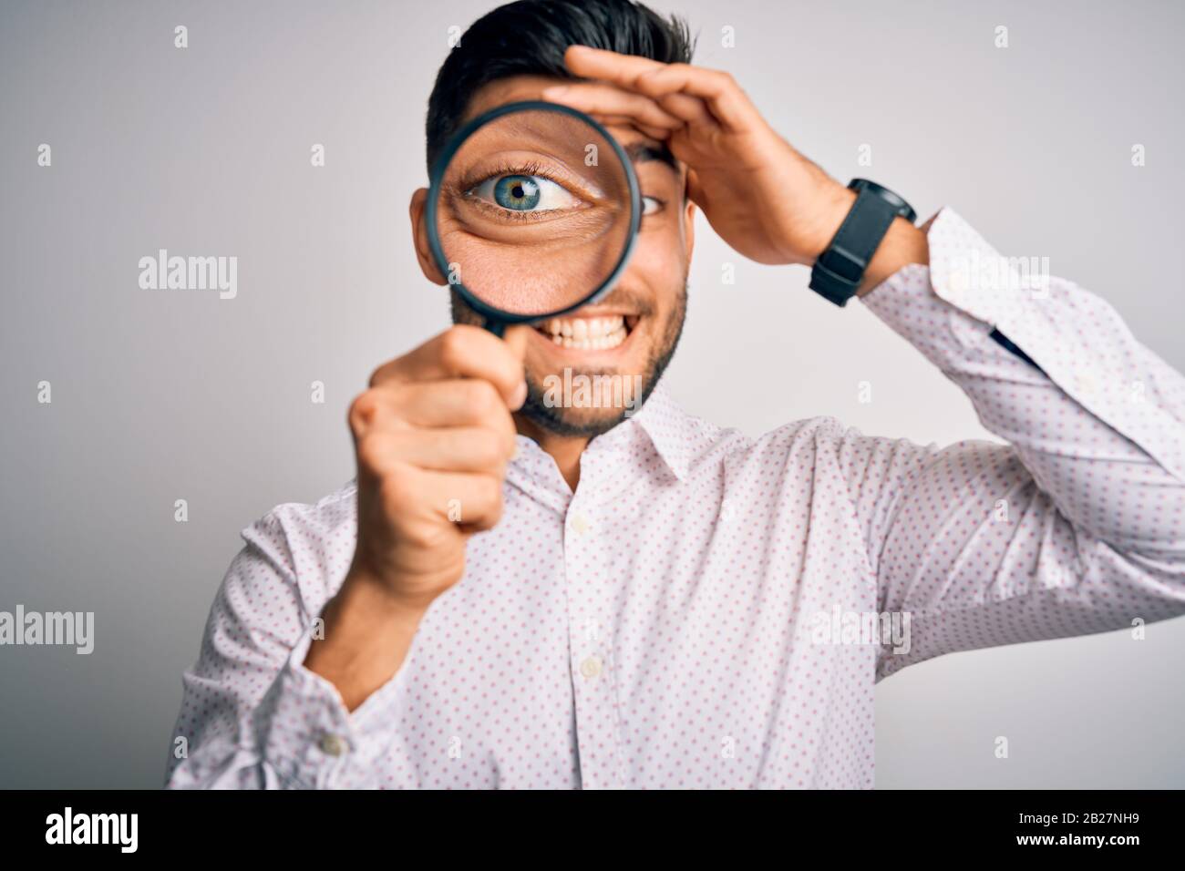 Young detective man looking through magnifying glass over isolated ...