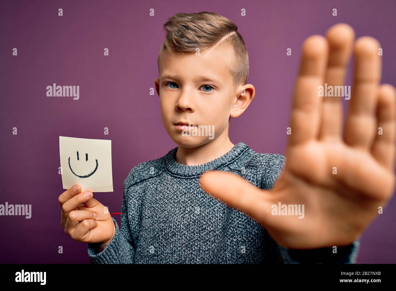 Young little caucasian kid showing smiley face on a paper note as happy ...