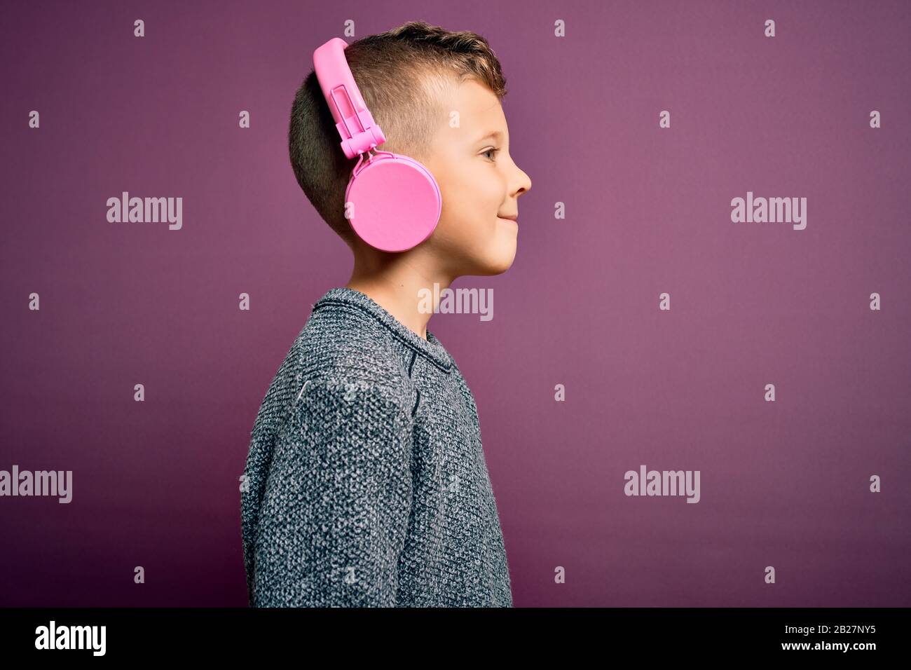 Young little caucasian kid wearing headphones listening to music over ...