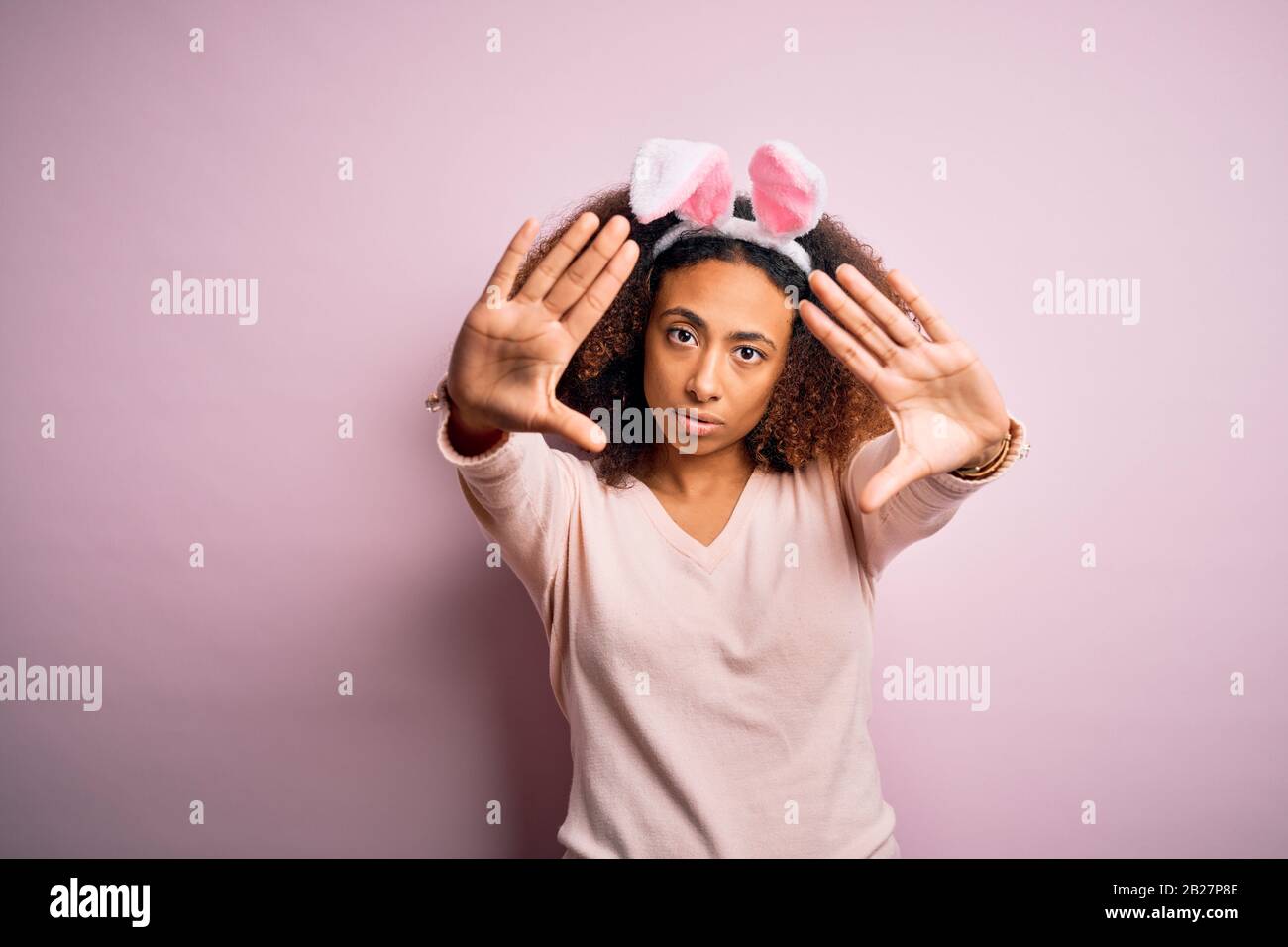 Young african american woman with afro hair wearing bunny ears over ...