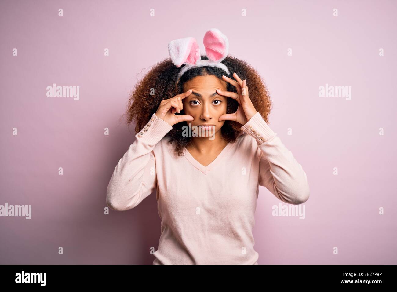 Young african american woman with afro hair wearing bunny ears over ...