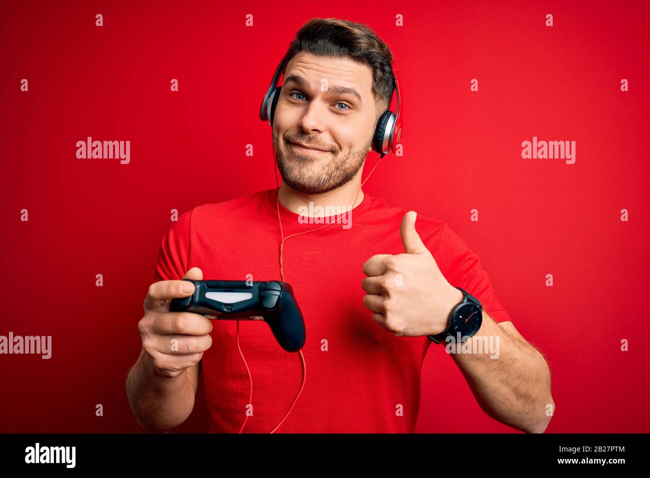 Young gamer man with blue eyes playing video games using gamepad ...