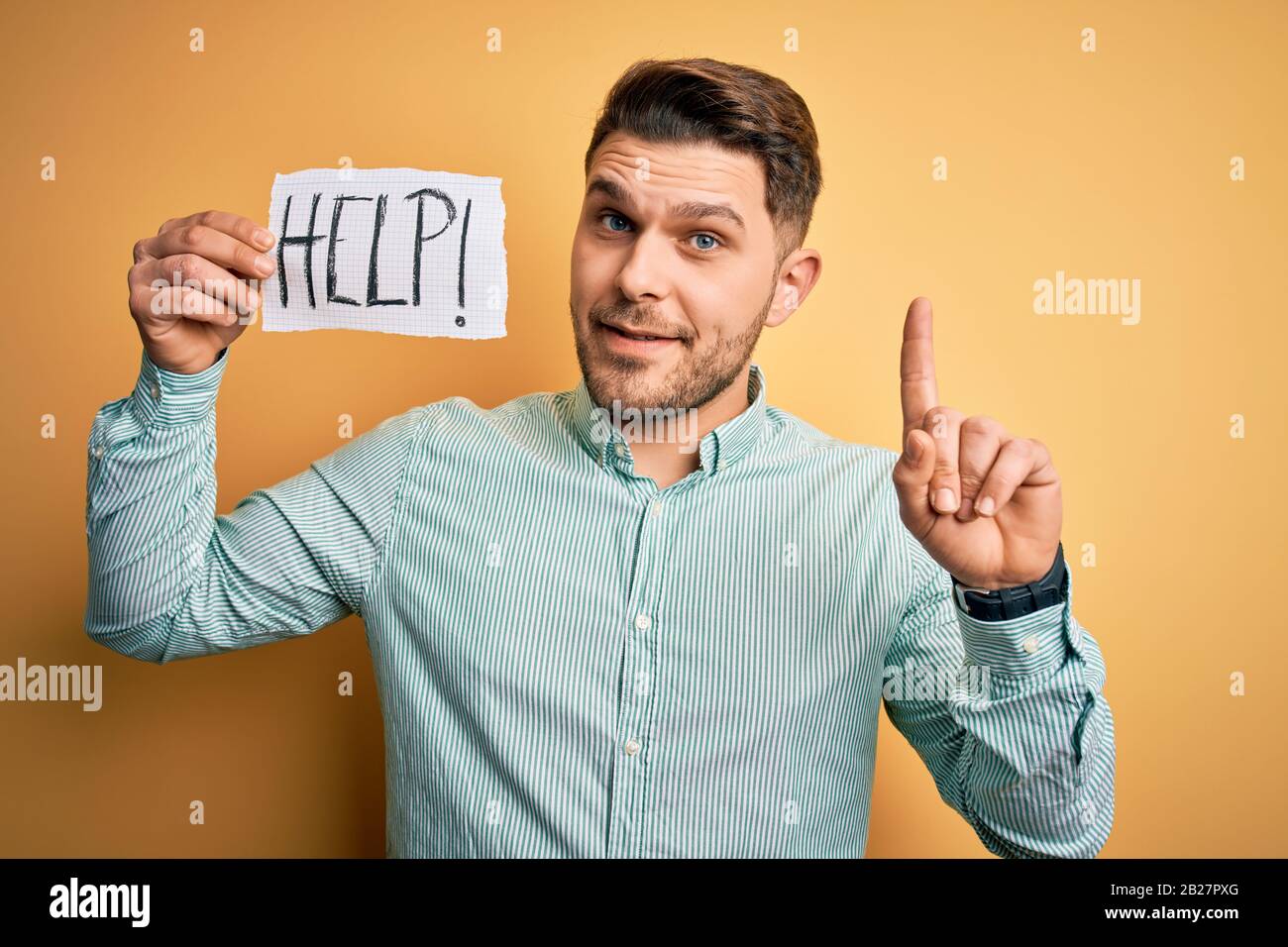 Young business man with blue eyes asking for help holding paper note ...
