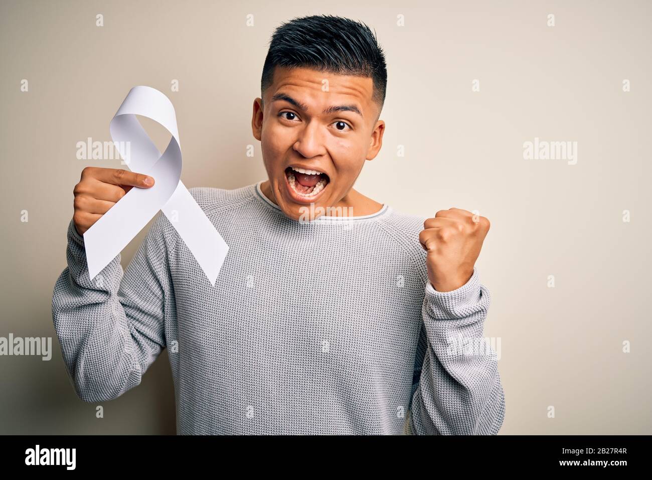 Young latin man holding white cancer ribbon supporting stop women ...