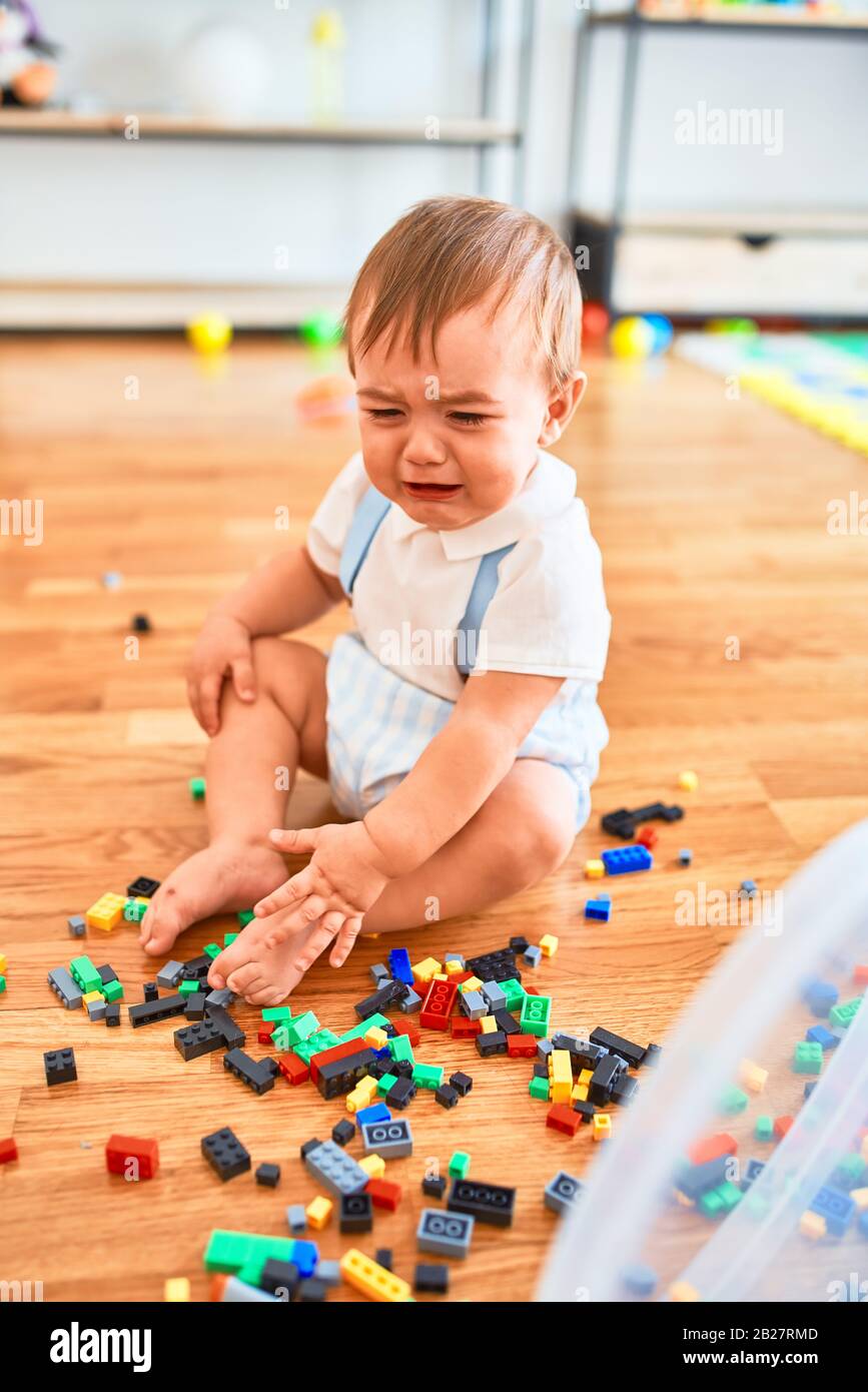 Adorable toddler crying around lots of toys at kindergarten Stock Photo ...