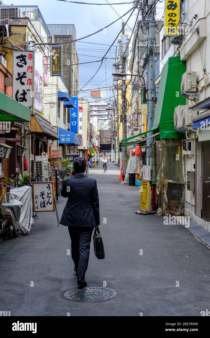 Businessman walks through a typical small street in Tokyo, Japan in ...