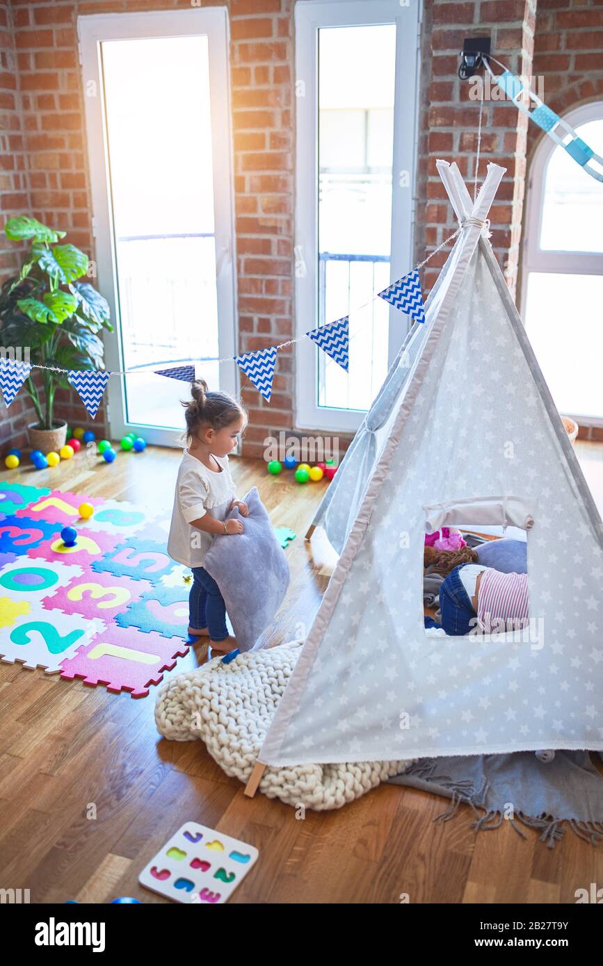 Adorable toddlers lying down over blanket inside tipi smiling at ...