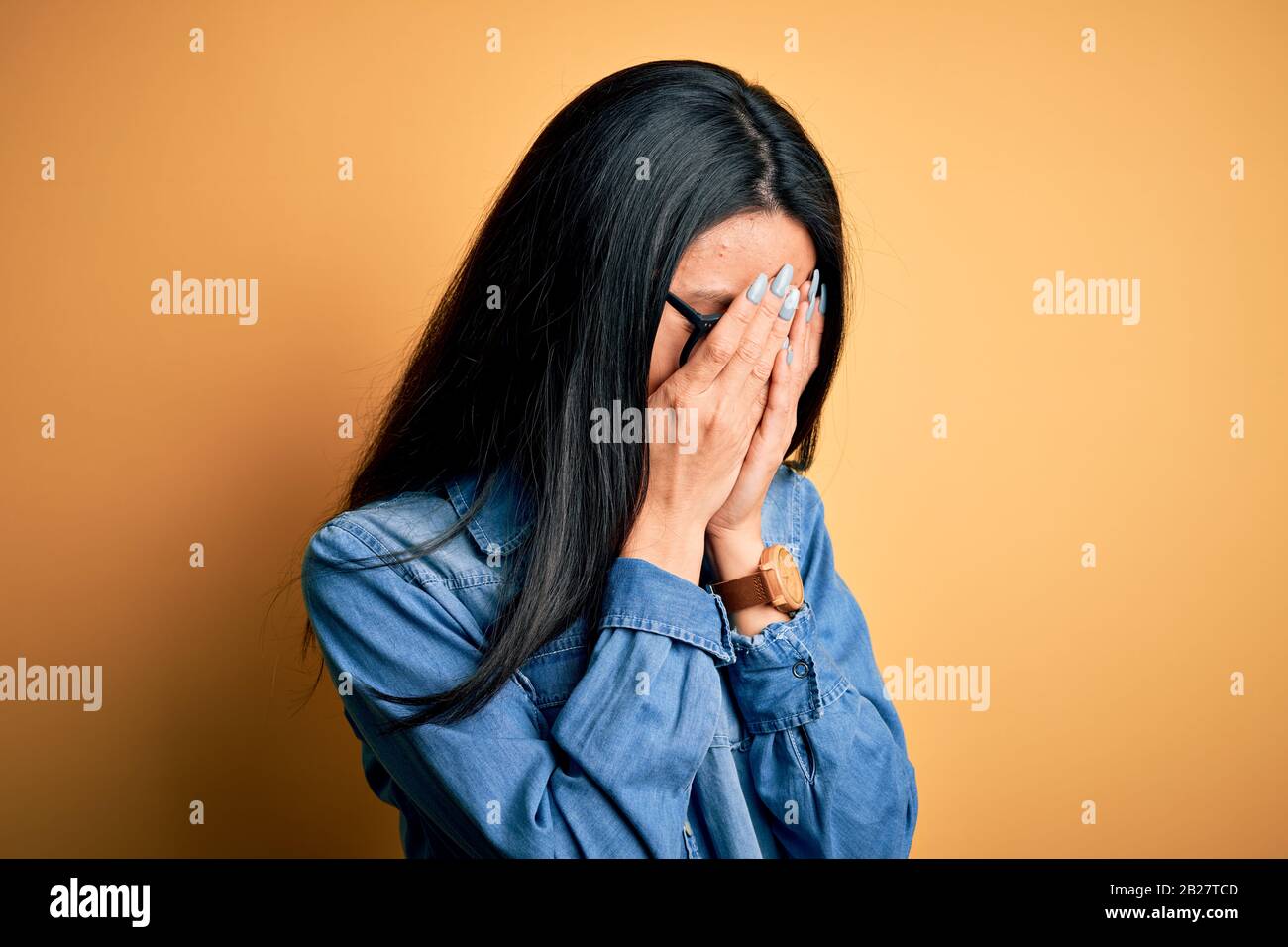 Young beautiful chinese woman wearing casual denim shirt over isolated ...