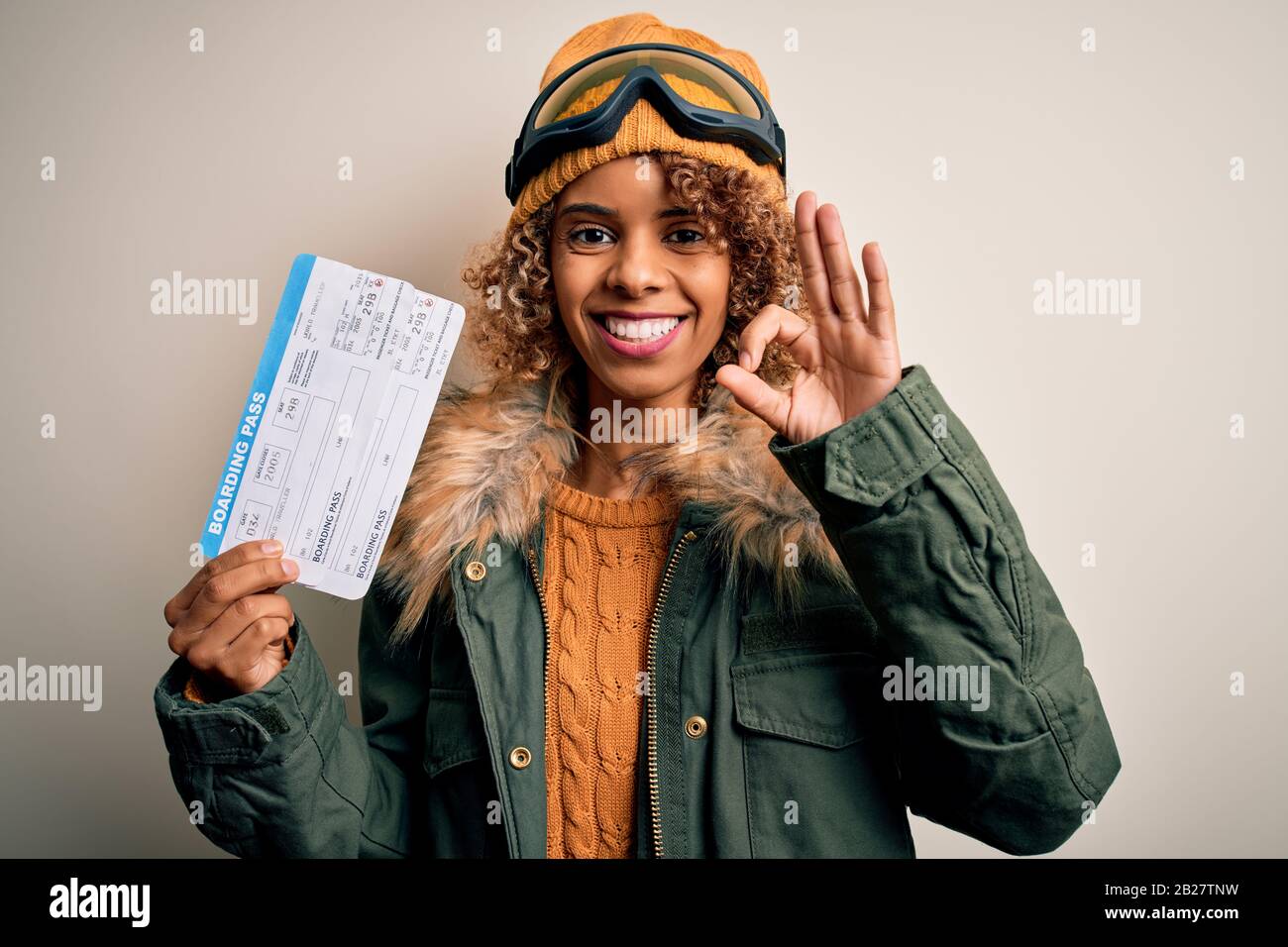 Young african american tourist woman wearing ski goggles holding plane ...