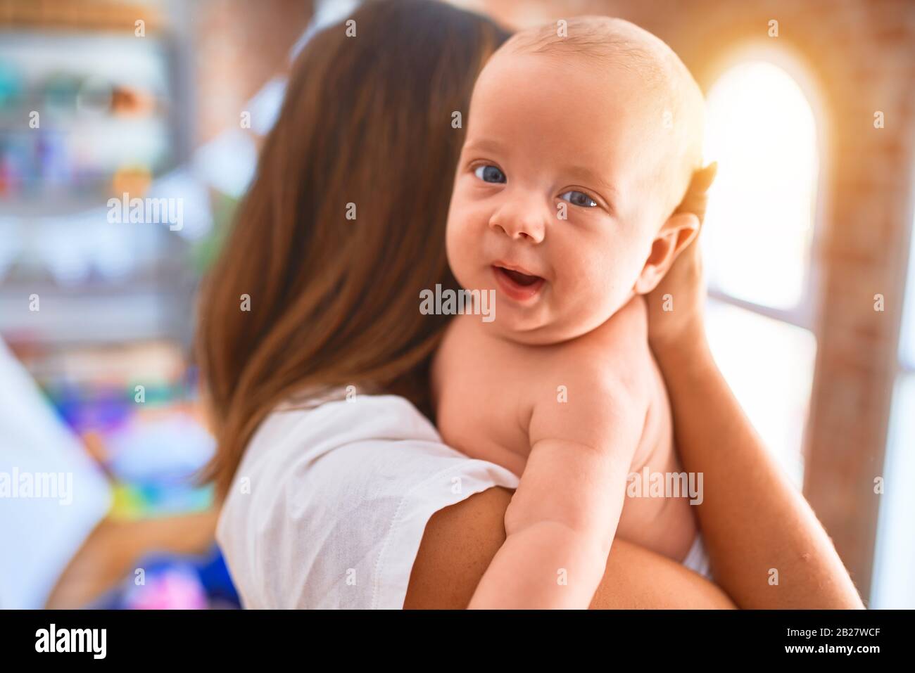Young beautifull woman and her baby standing at home. Mother holding ...