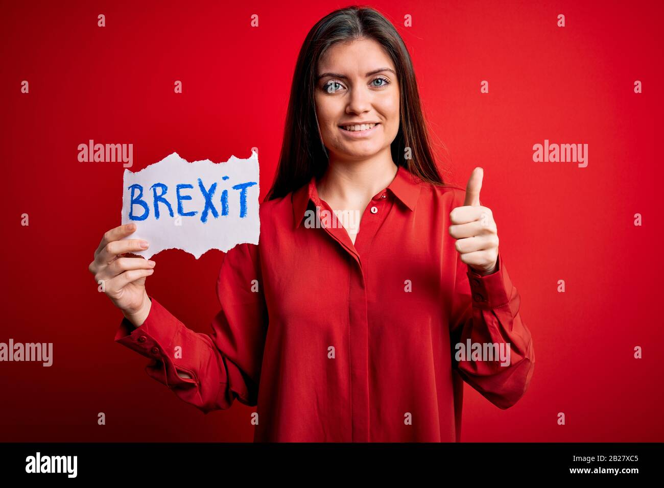 Young beautiful woman with blue eyes holding paper with brexit message ...