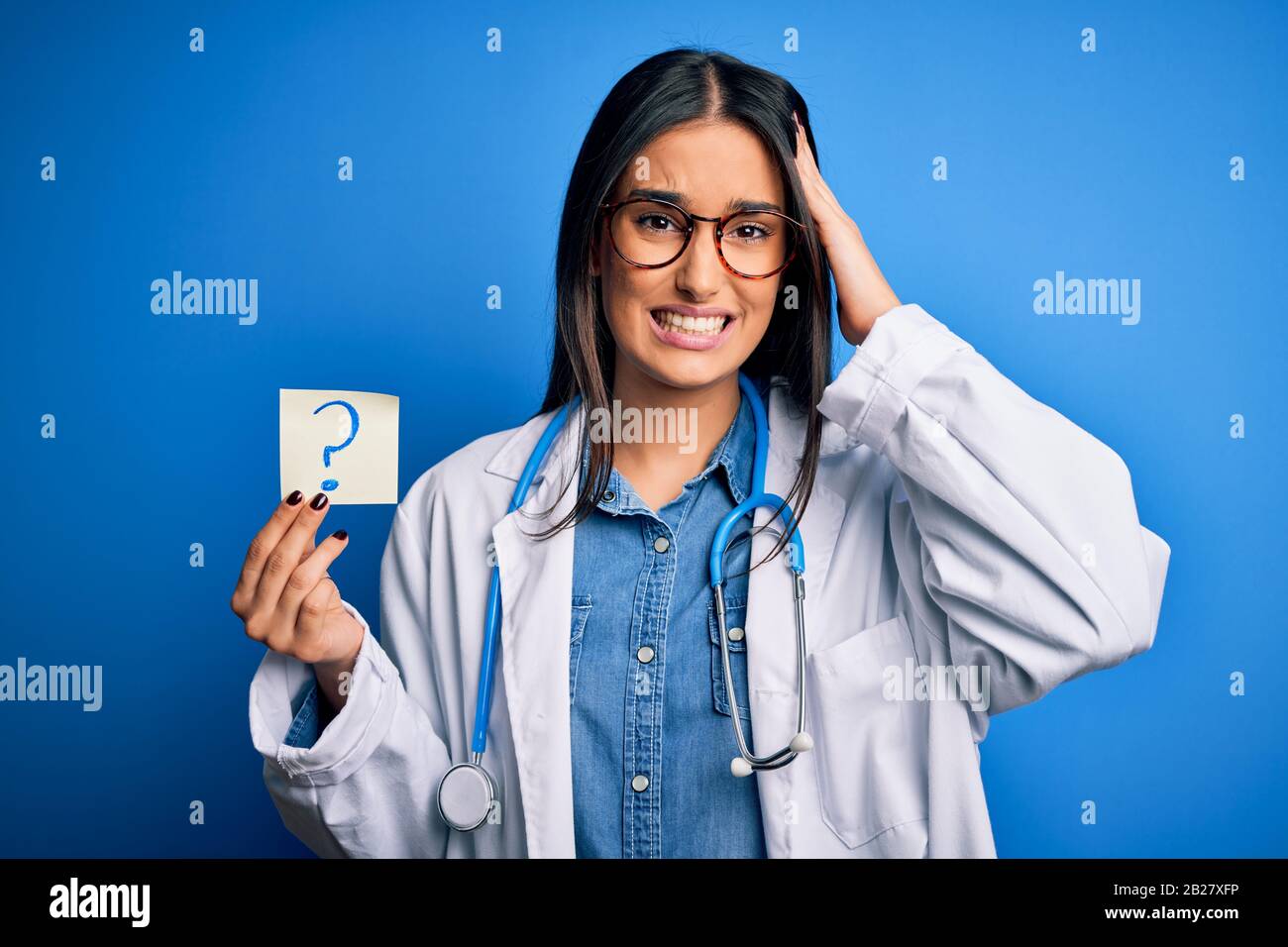 Young beautiful brunette doctor woman holding paper with question mark ...