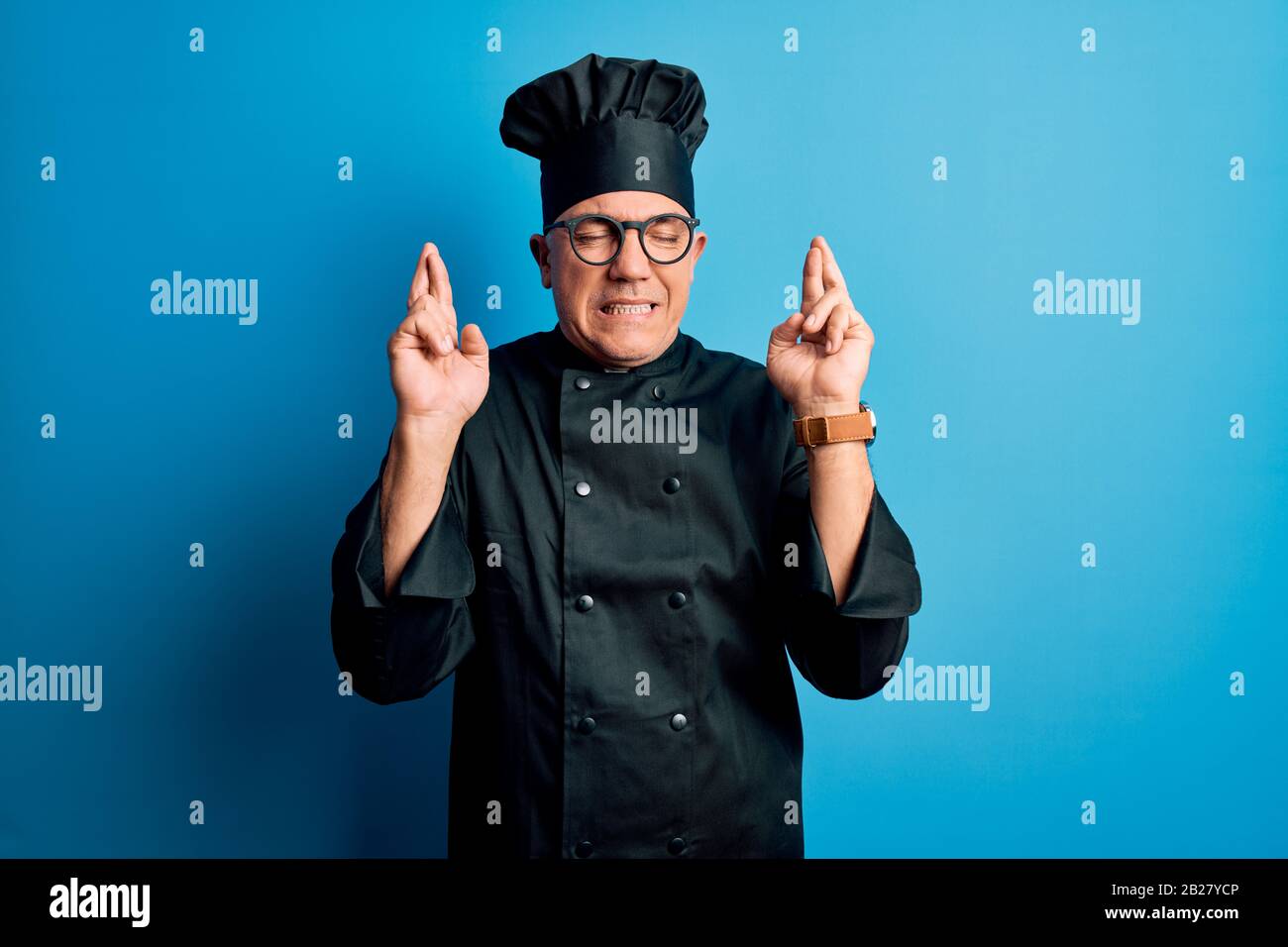 Middle age handsome grey-haired chef man wearing cooker uniform and hat ...