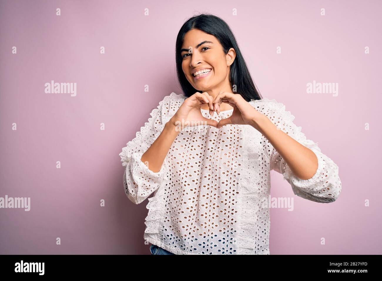Young beautiful hispanic fashion woman wearing elegant shirt over pink ...