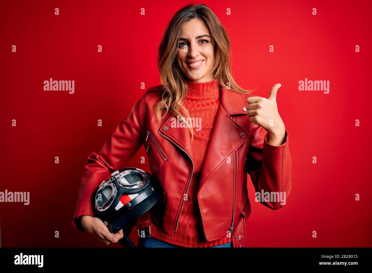 Beautiful brunette motorcyclist woman wearing red jacket holding ...