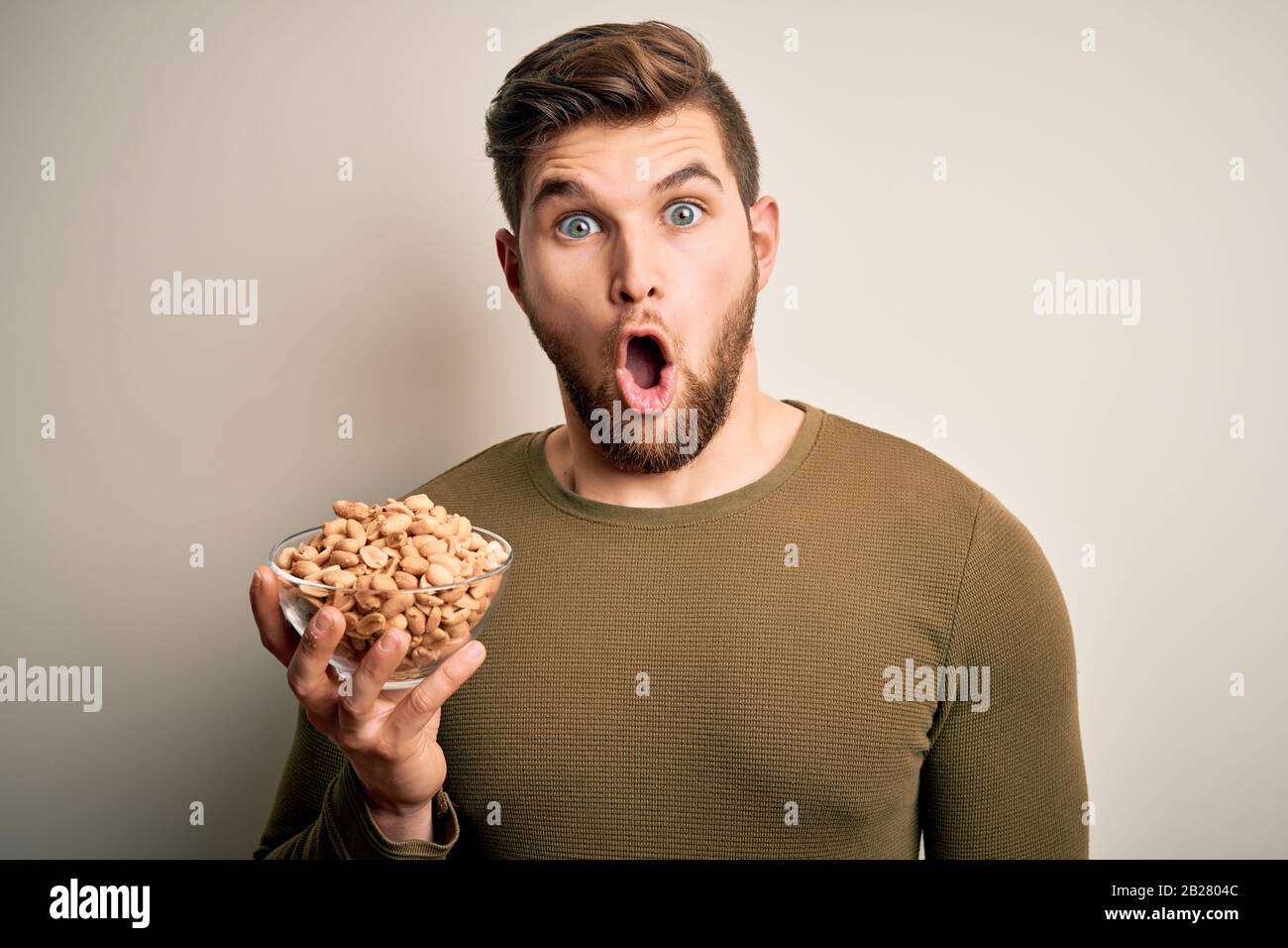 Young blond man with beard and blue eyes holding bowl with healthy ...
