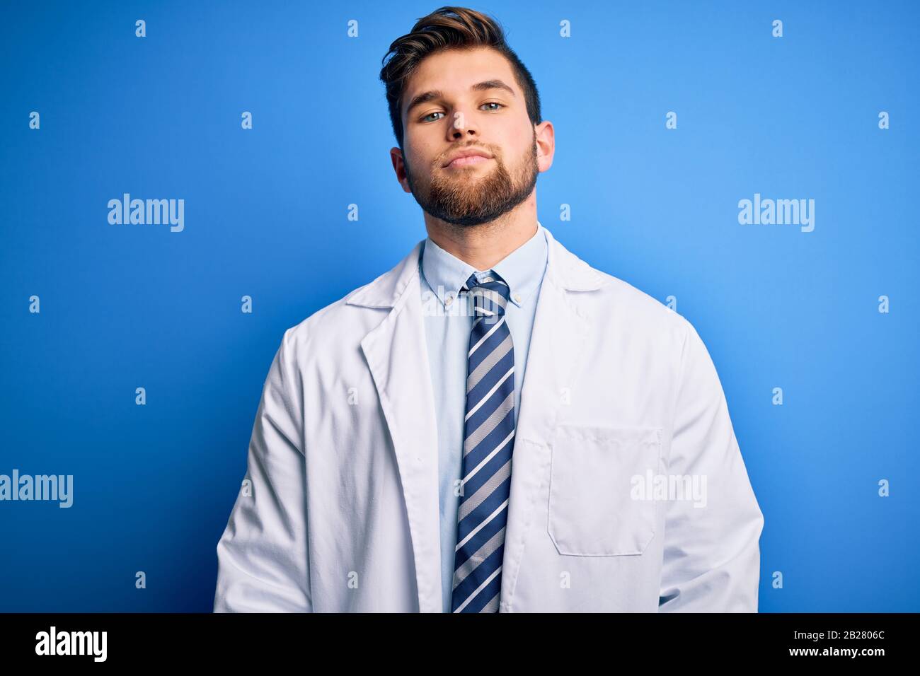 Young blond therapist man with beard and blue eyes wearing coat and tie ...