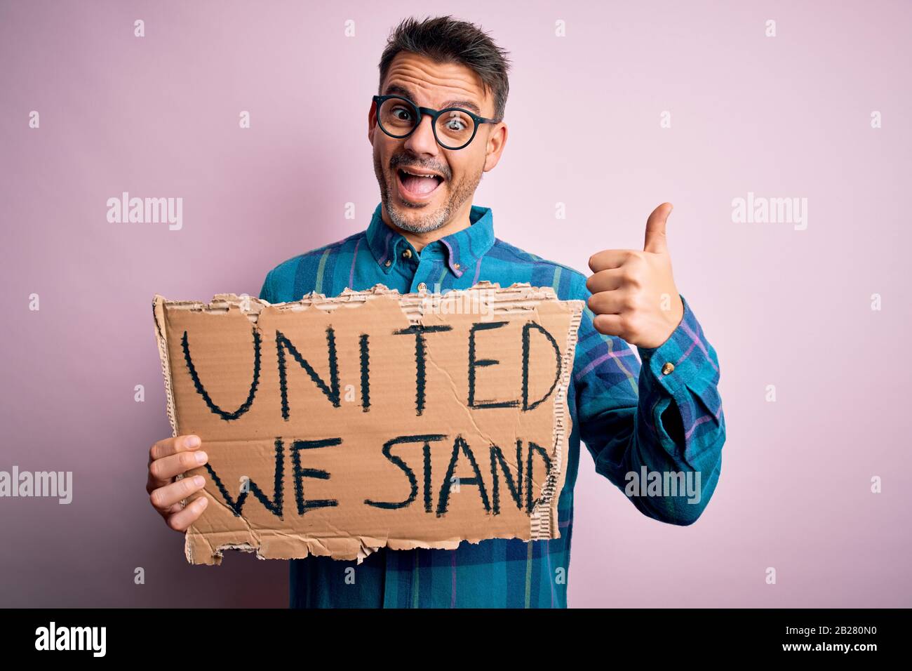 Young handsome activist man asking for union holding banner with united ...