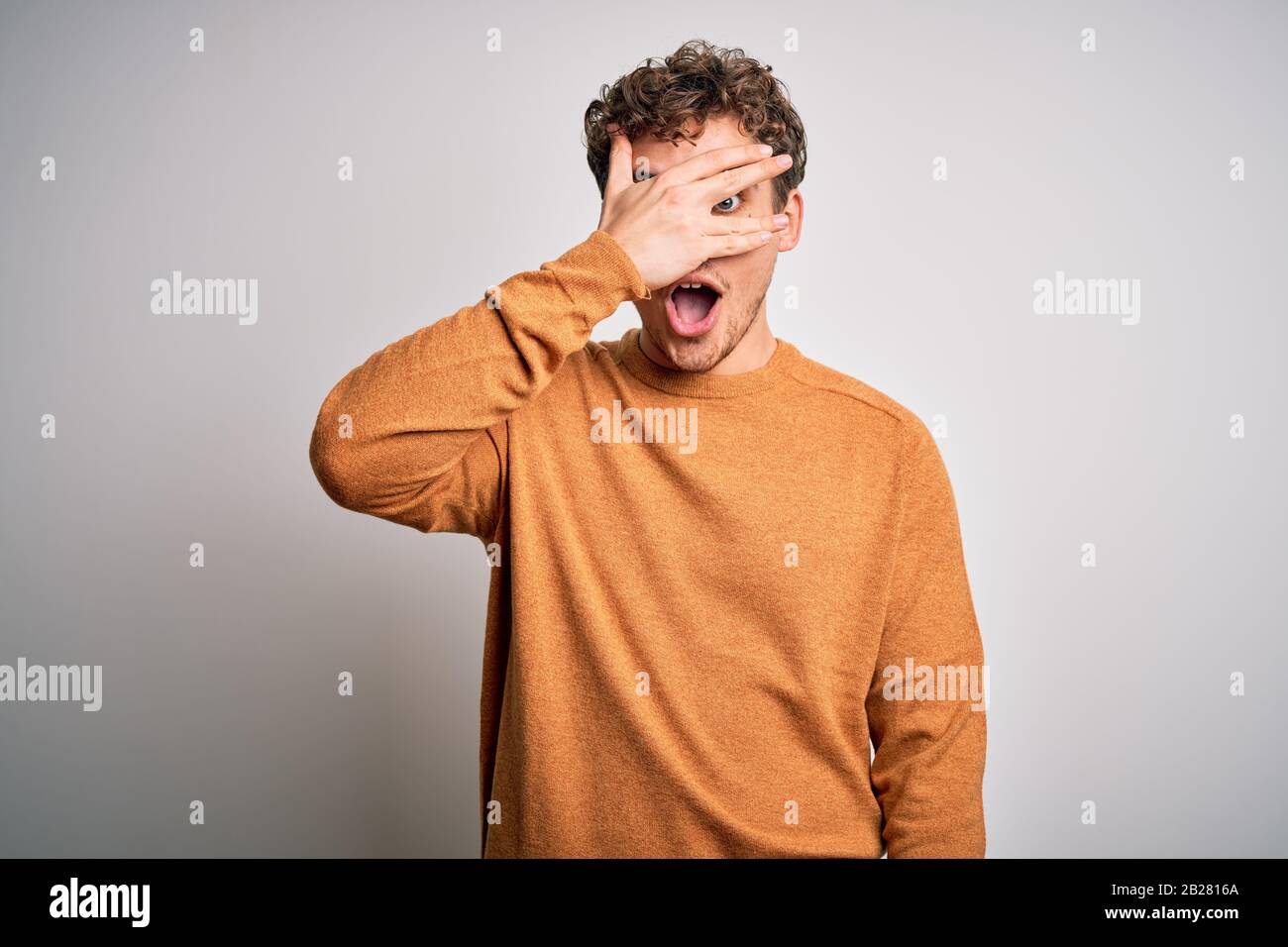Young blond handsome man with curly hair wearing casual sweater over ...