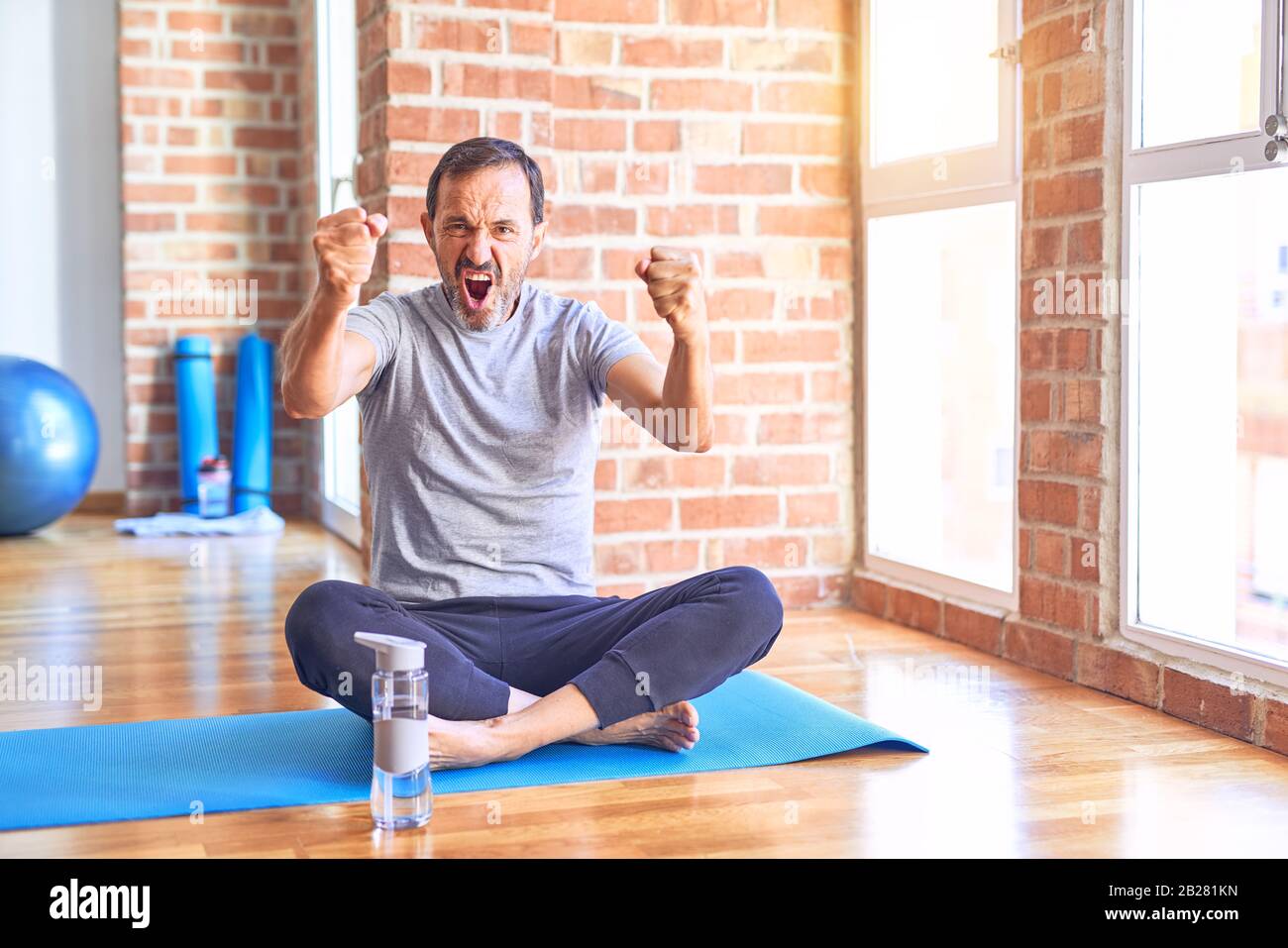 Middle age handsome sportman sitting on mat doing stretching yoga ...