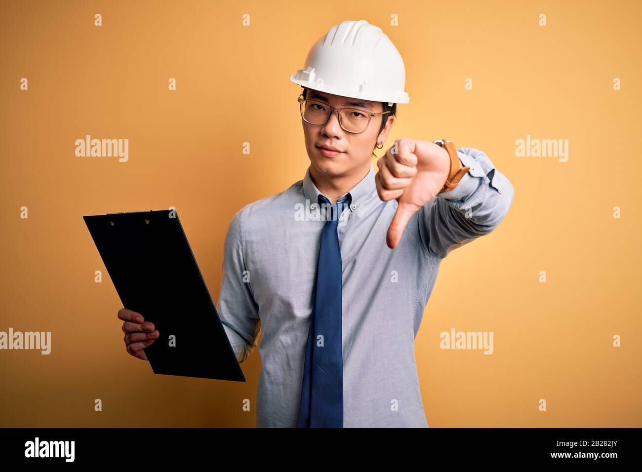 Young handsome chinese engineer man wearing safety helmet holding ...
