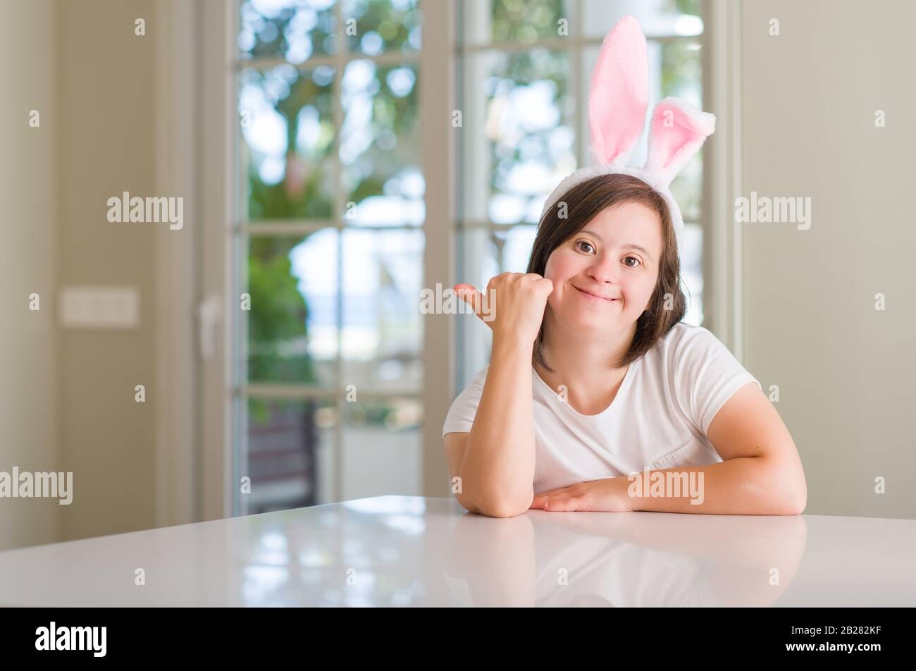 Down syndrome woman at home wearing easter rabbit ears pointing and ...