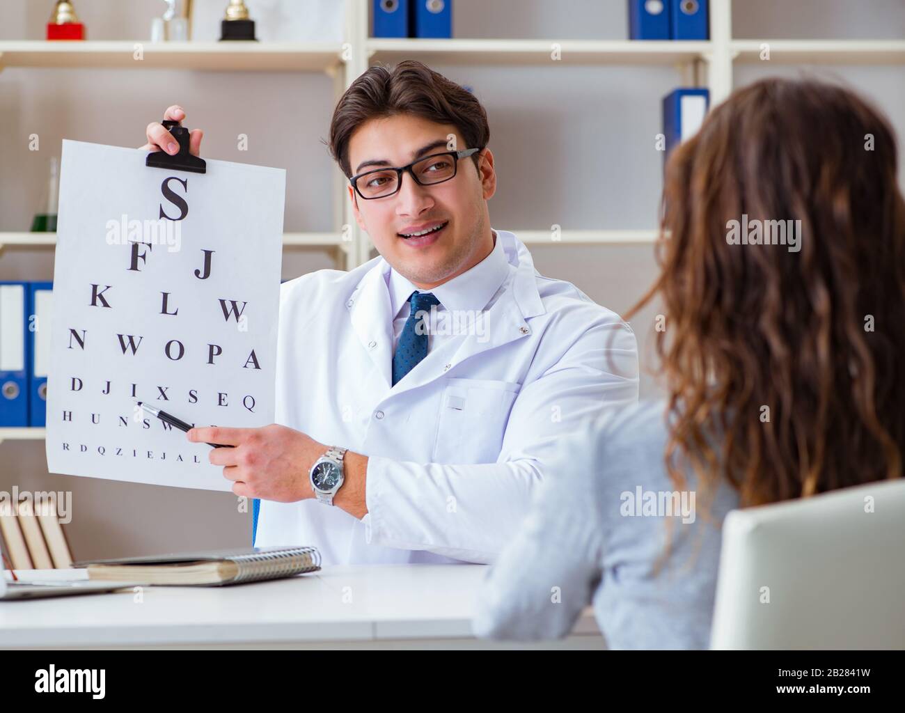 The doctor optician with letter chart conducting an eye test check ...