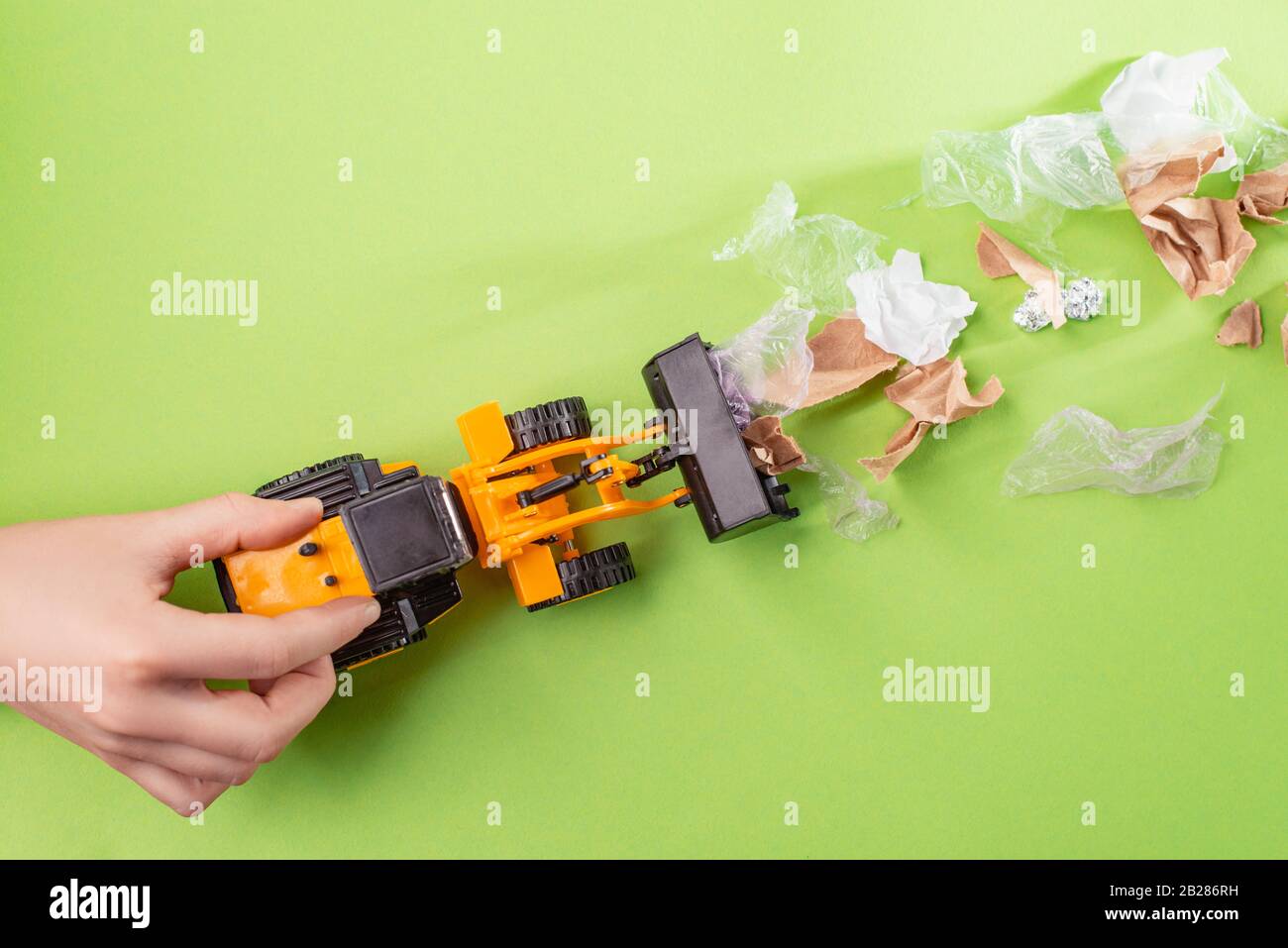 Child playing with a toy truck and collecting garbage on the paper lawn ...