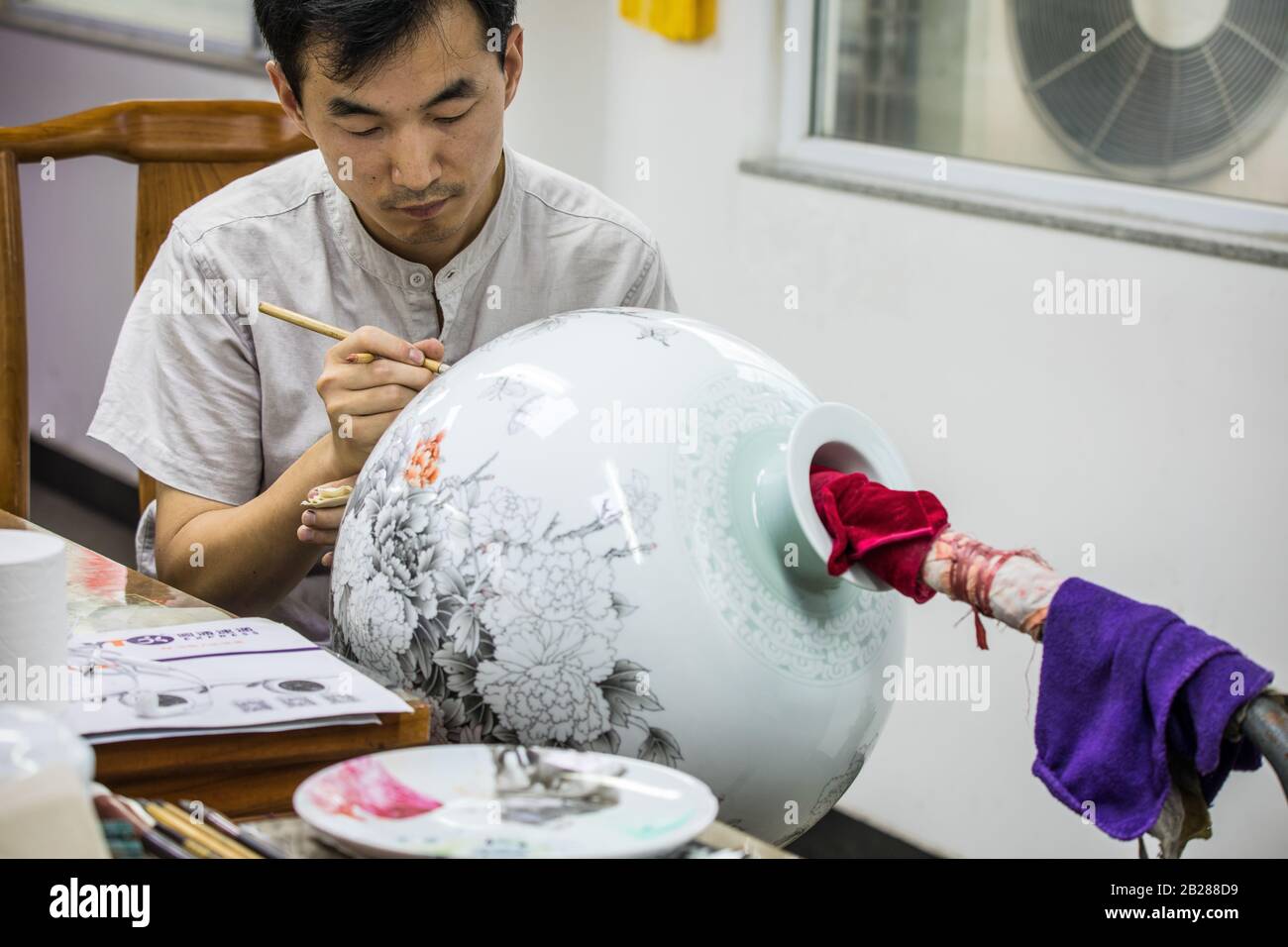 BEIJING, СHINA - JUNE 03: Chinese craftsman paints a large porcelain ...