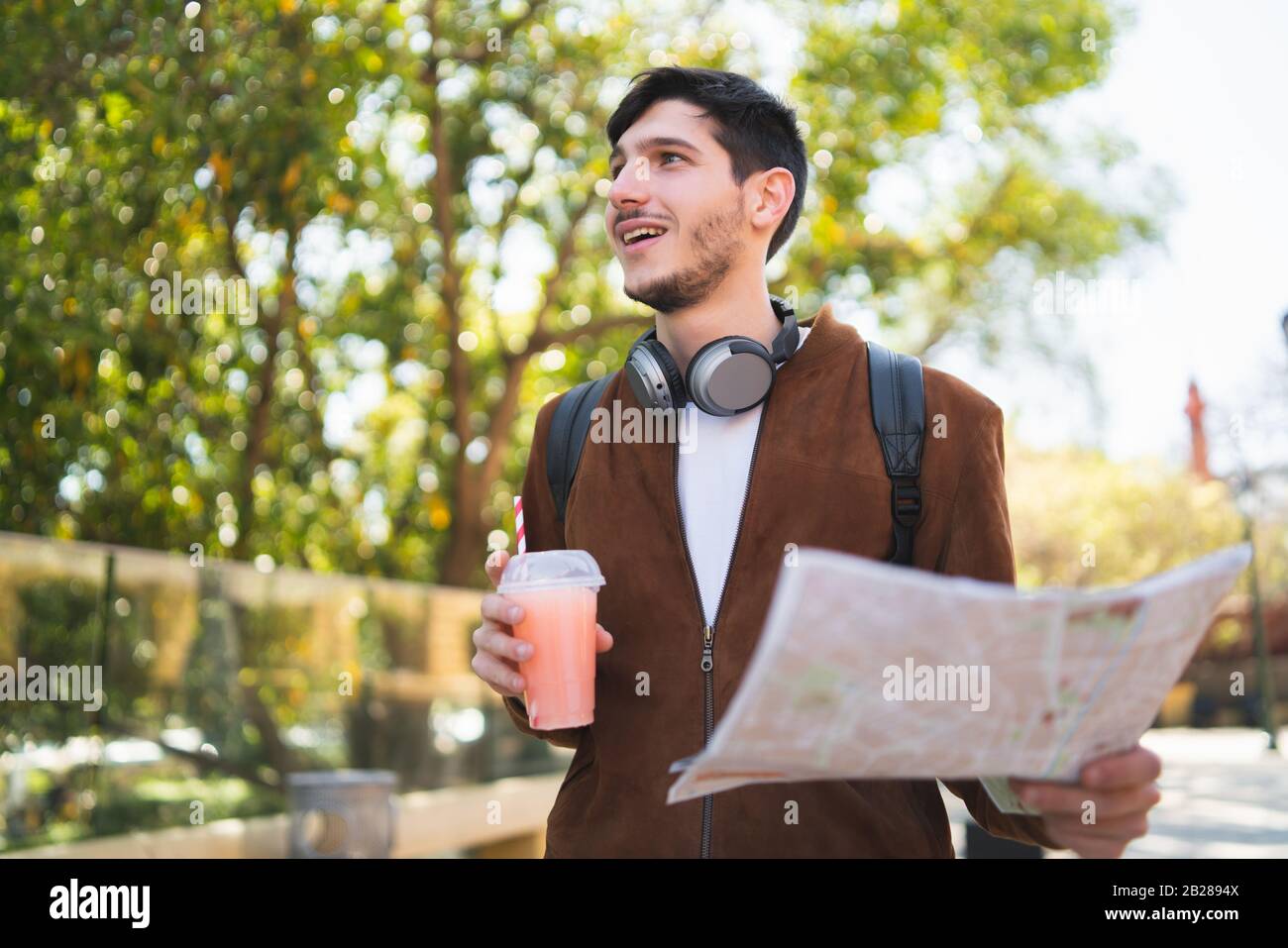 Portrait of young traveler man holding a map and looking for directions ...
