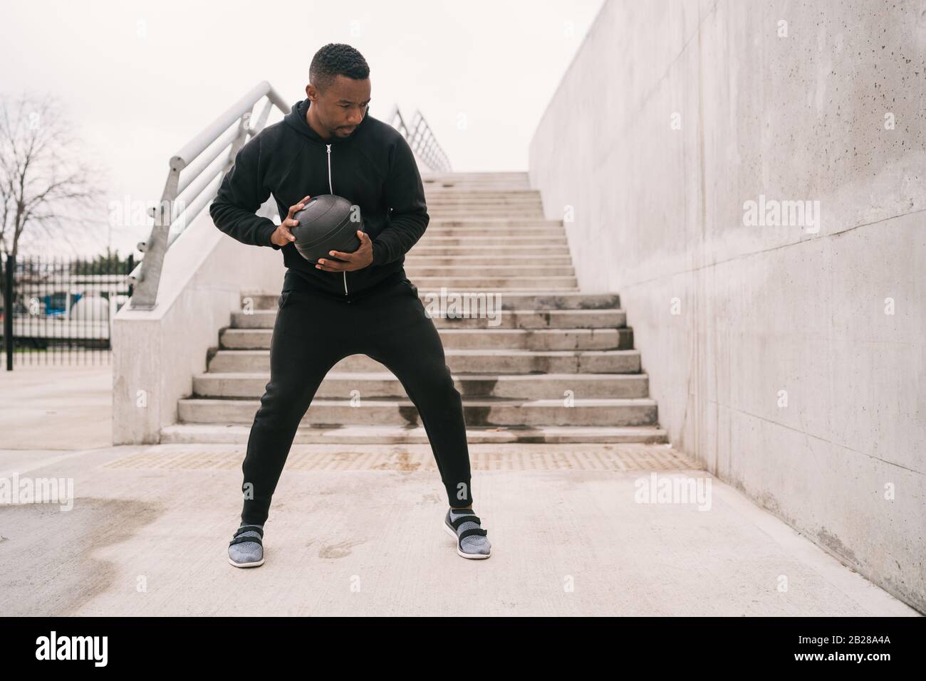 Portrait of an athletic man doing wall ball exercise outdoors. Sport ...