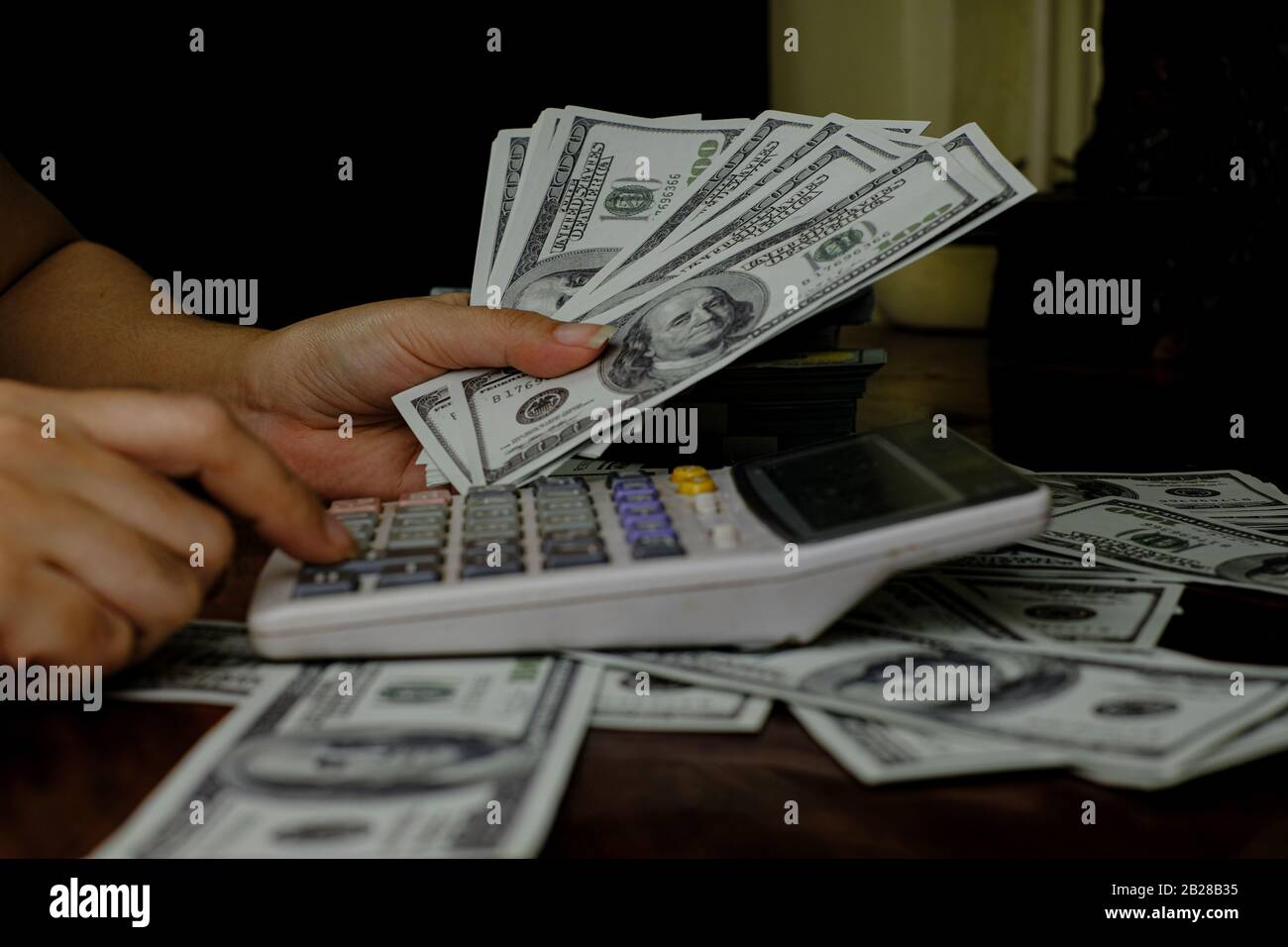 Businessmen women counting money on a stack of 100 US dollars banknotes ...