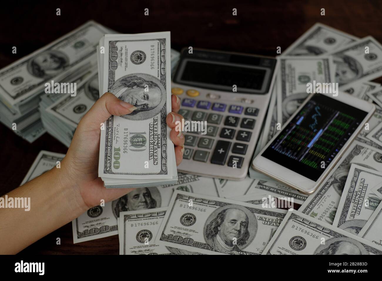 Businessmen women counting money on a stack of 100 US dollars banknotes ...