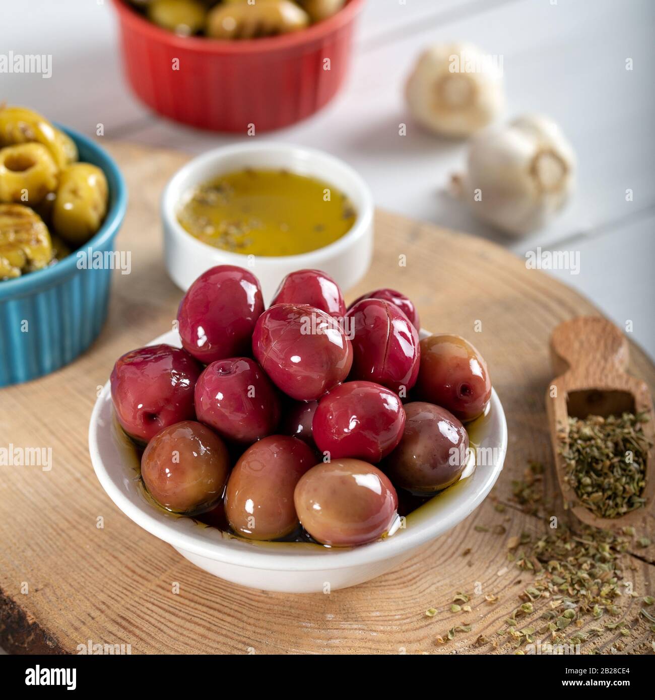 Green and red olives in bowl with olive oil and spices on wooden ...