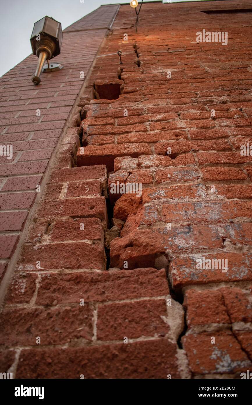 Red brick exterior downtown wall of a building with a large crack ...