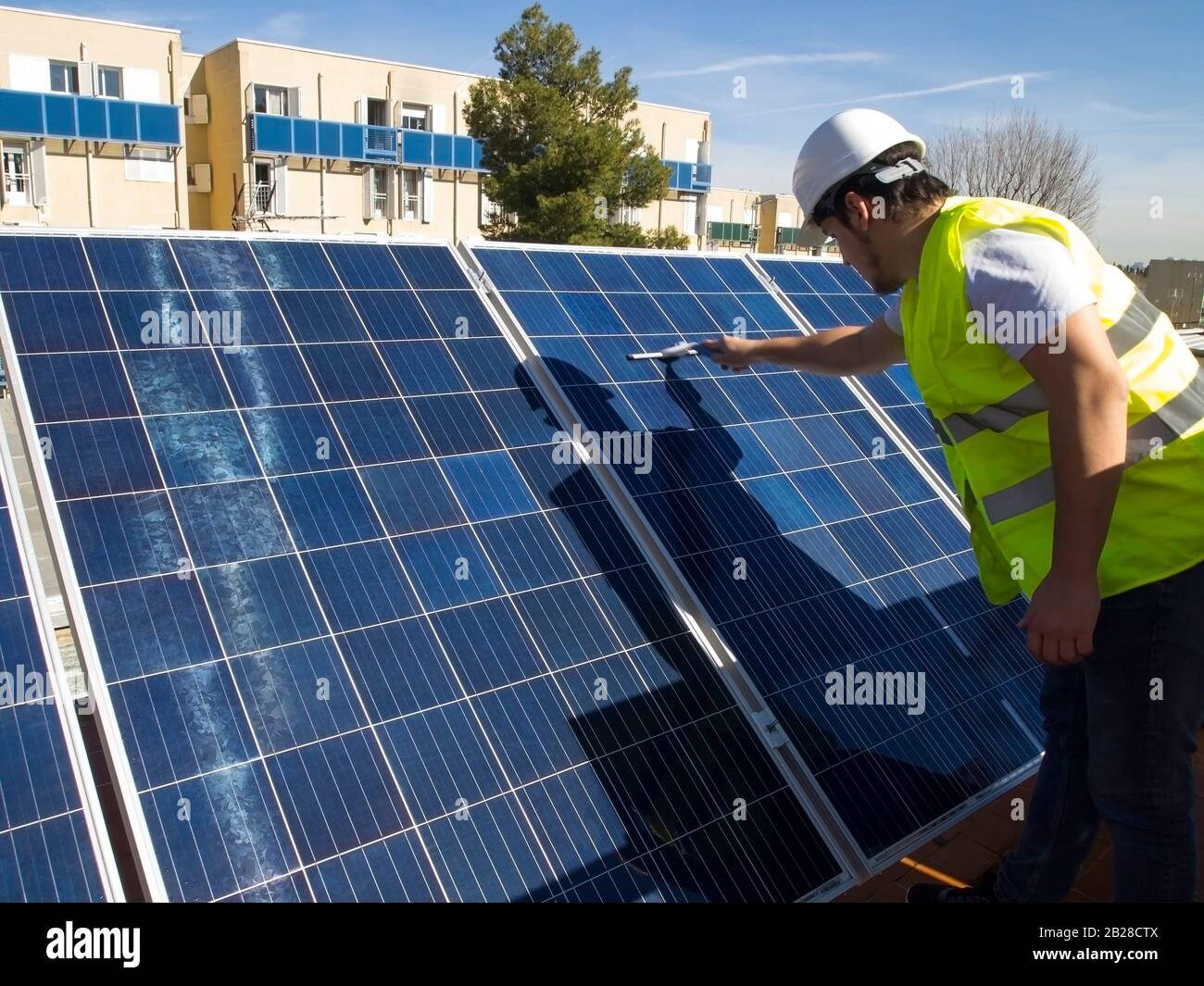 Caucasian attractive young technician cleaning solar panels with a ...
