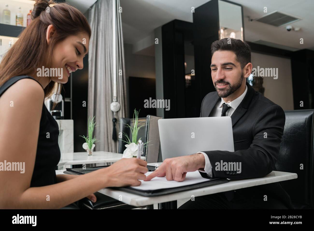 Portrait of two young business people having meeting in a hotel lobby ...