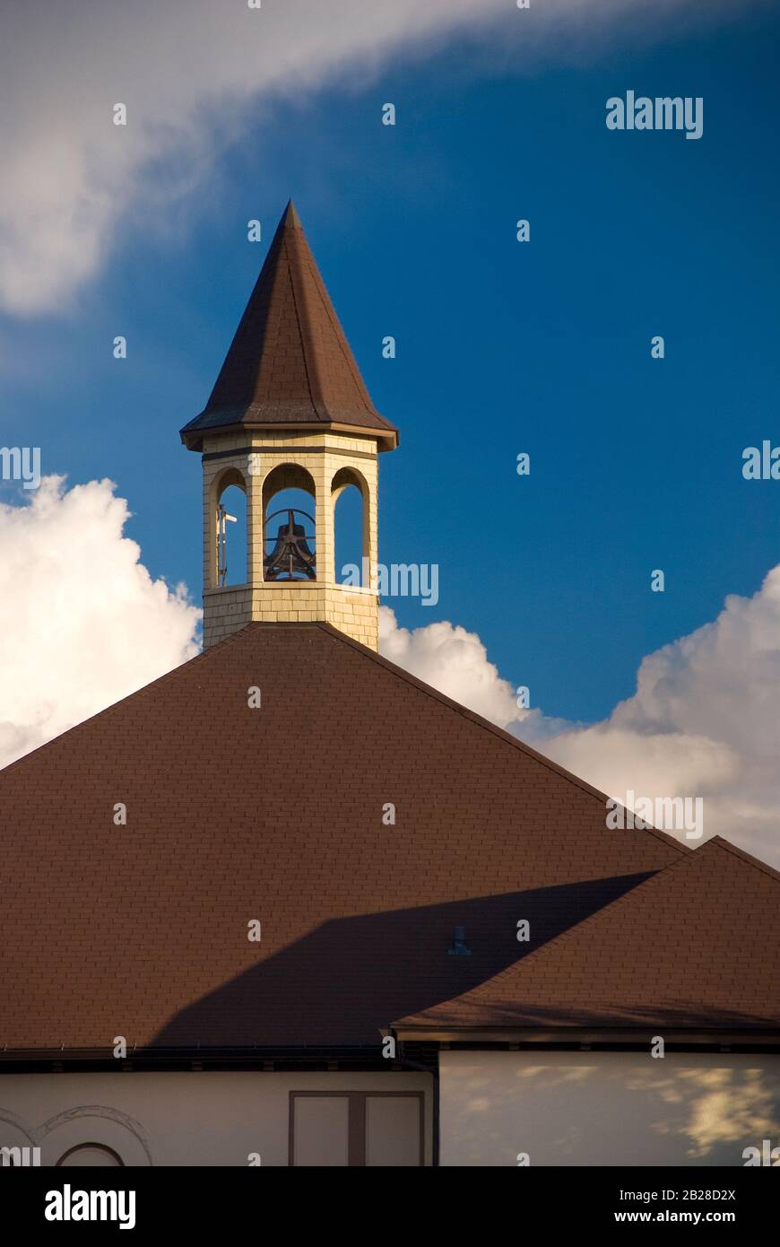 Tall Brown opened steeple with a large metal bell over a brown roof ...