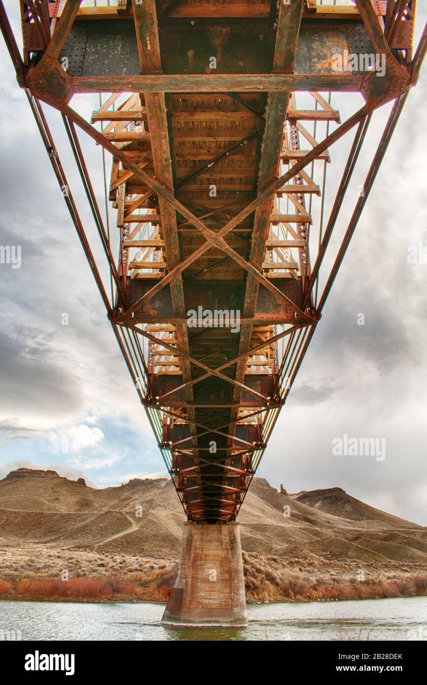 Long rusted bridge under a cloudy sky in a high desert scene looking up ...