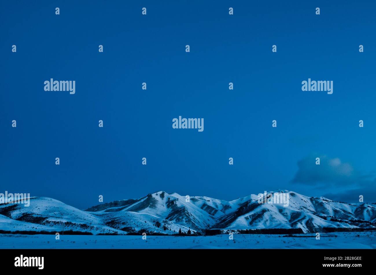 Early morning blue light barely illuminating the snow covered mountains ...