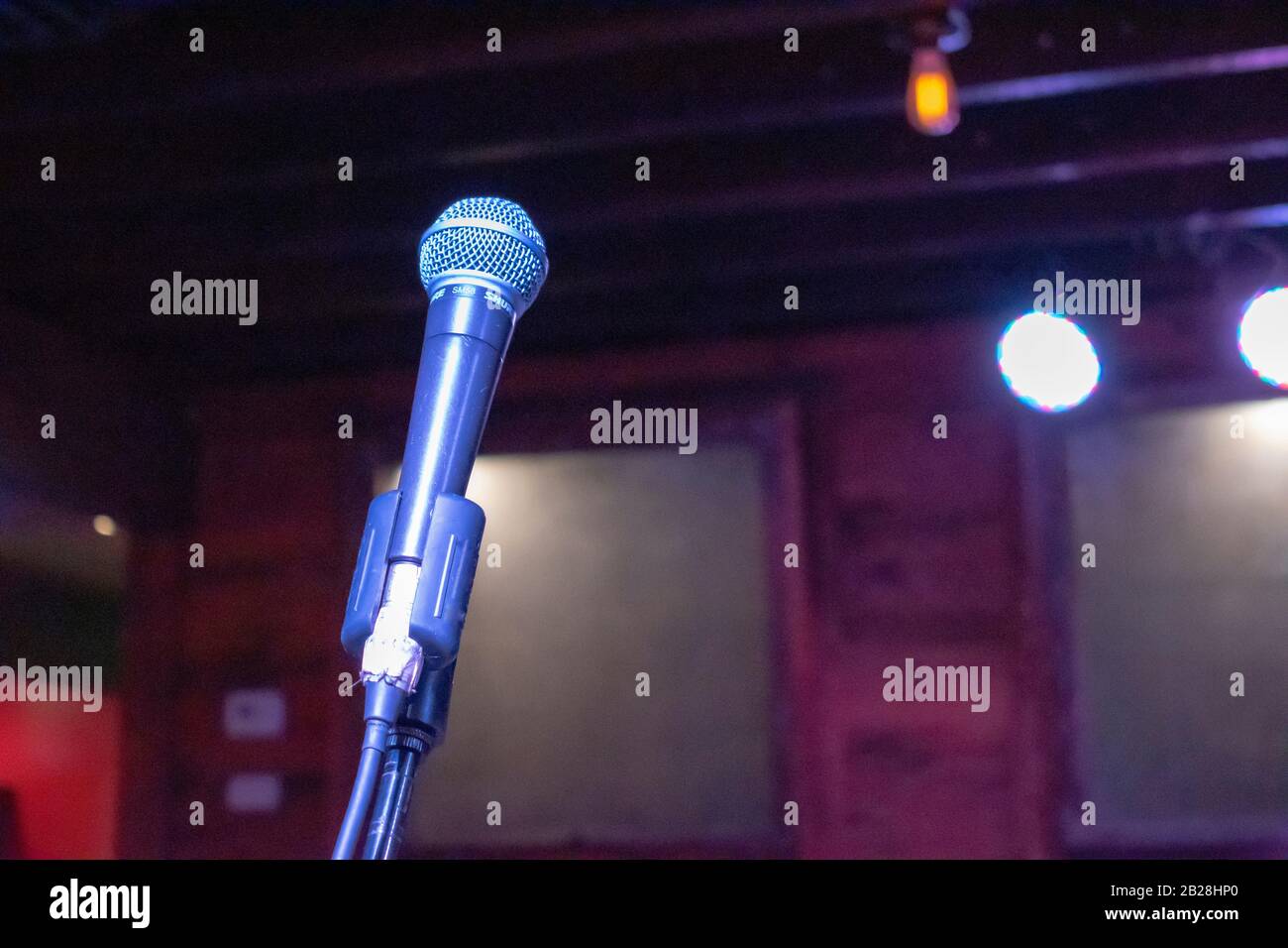 Single illuminated microphone waits the musician singer on the stage ...