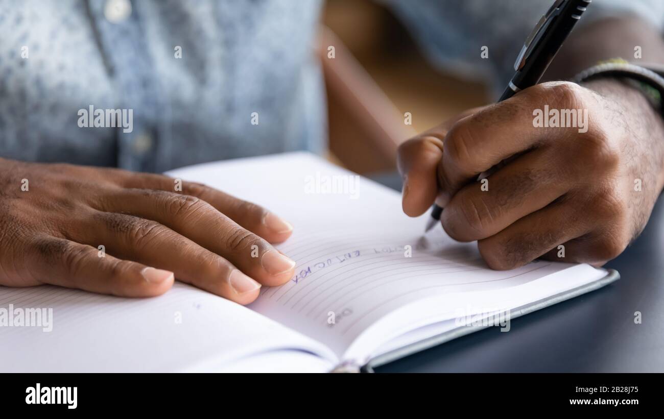 Close up young mixed race guy writing down notes Stock Photo - Alamy