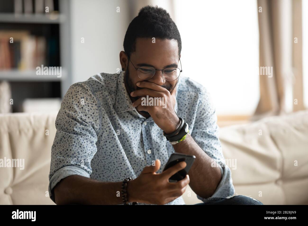 Funny young african ethnicity guy looking at cellphone screen Stock ...