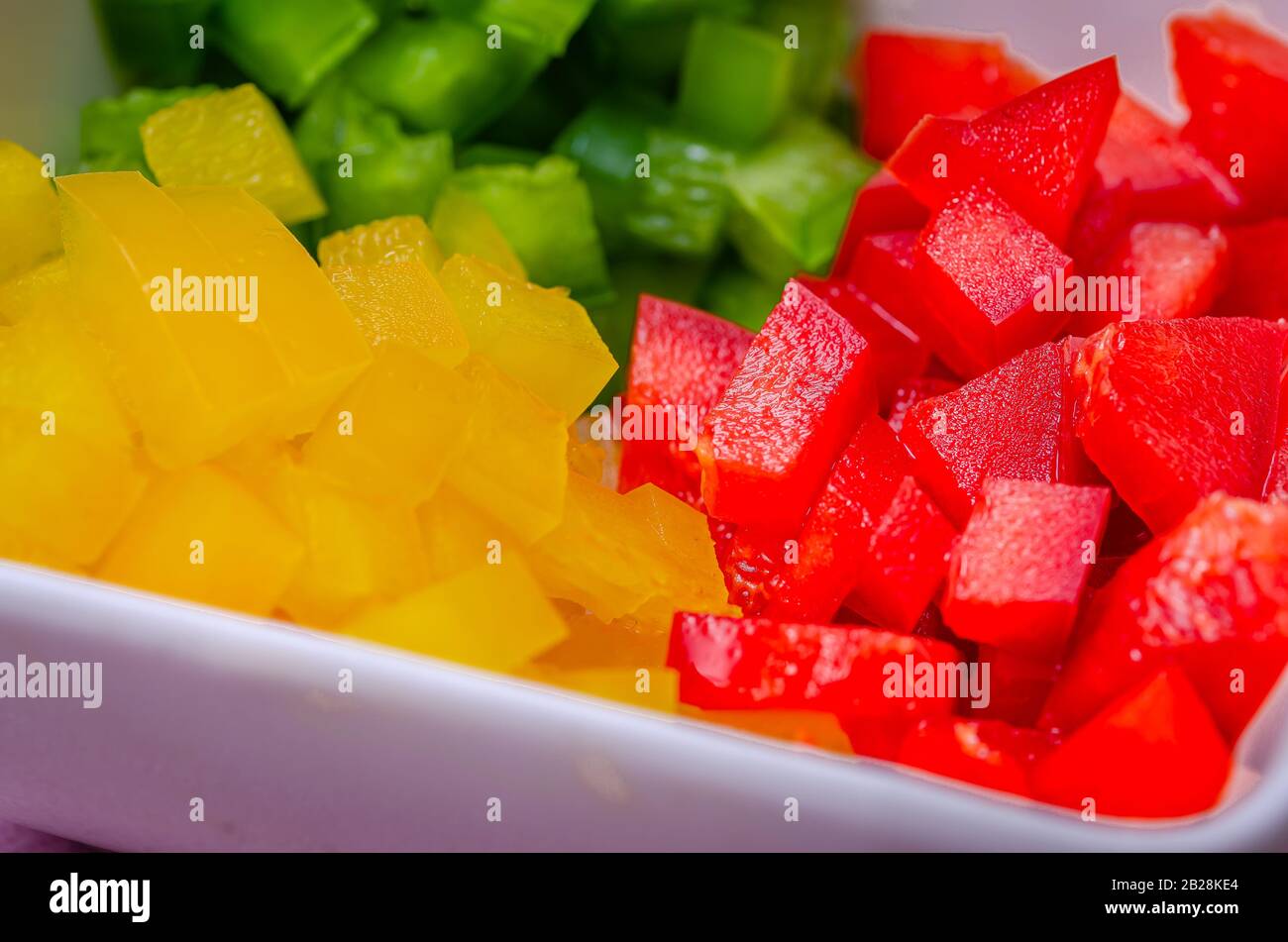 Close up of yellow, green and red capsicum chopped to small pieces in a ...