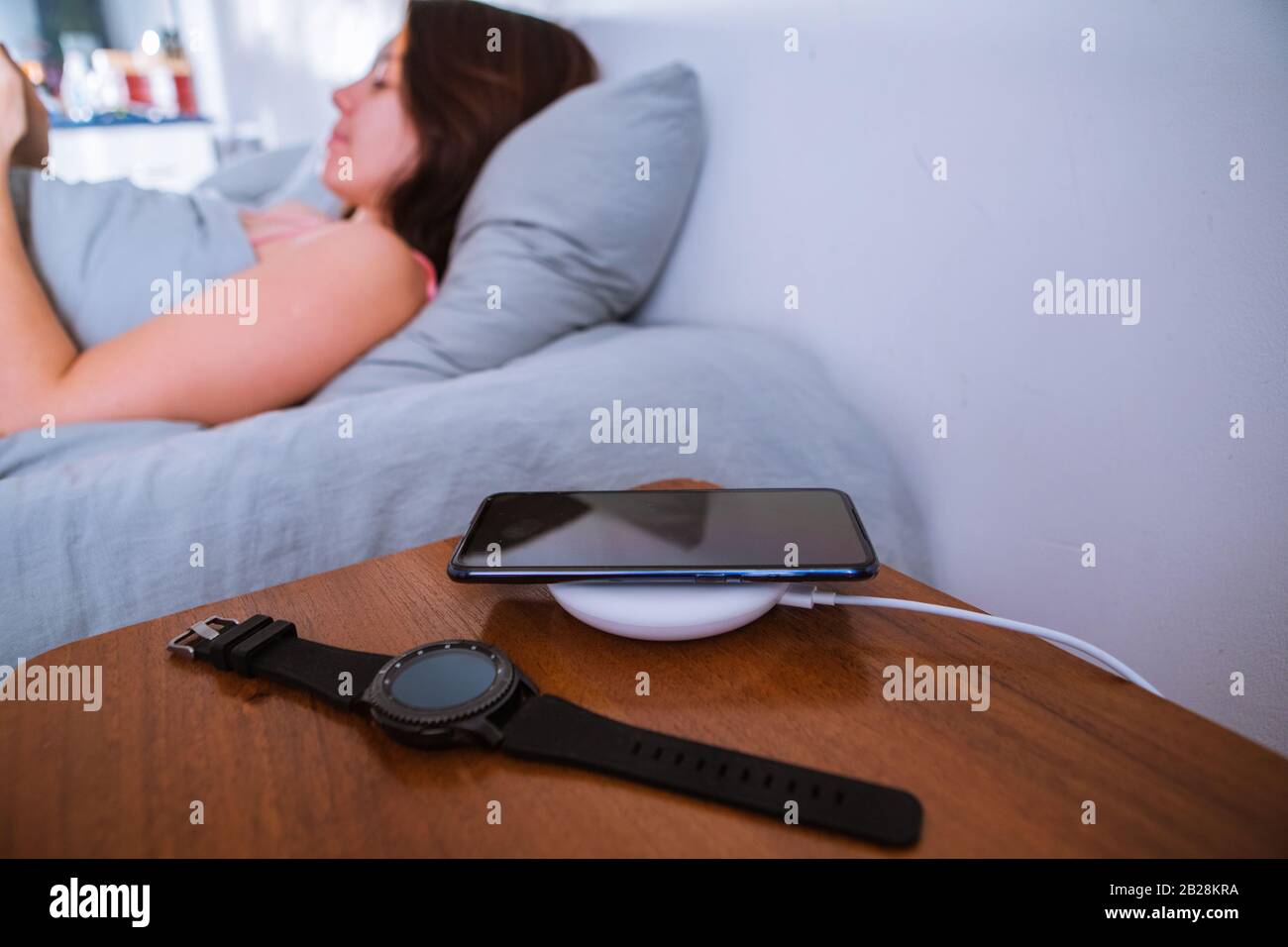 sleeping woman in bed cellphone charging on wireless charger Stock ...