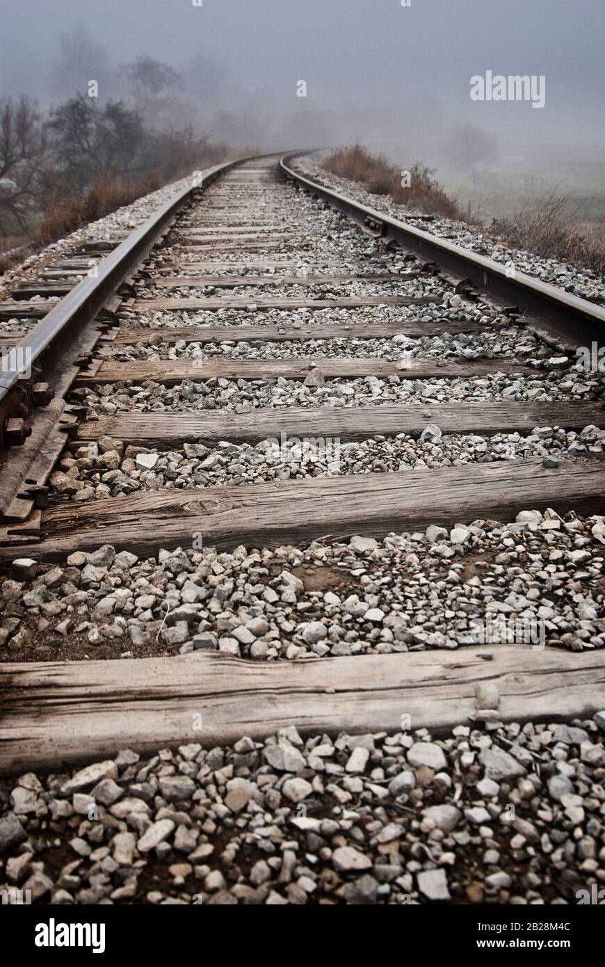 Metal Train tracks and wooden ties on a ballast bed leading around a ...