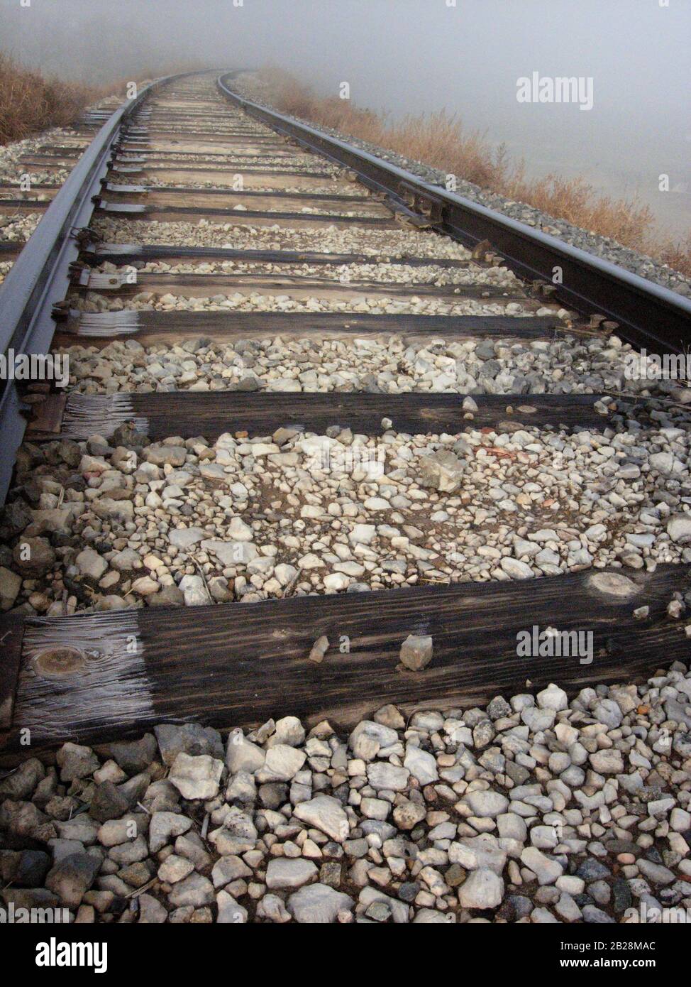 Metal Train tracks and wooden ties on a ballast bed leading around a ...