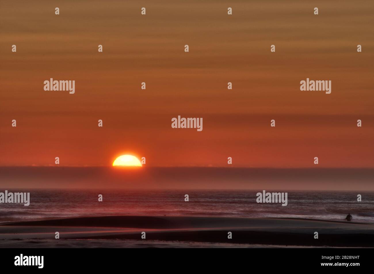 Orange Sun Setting behind the clouds framing the Pacific Ocean horizon ...